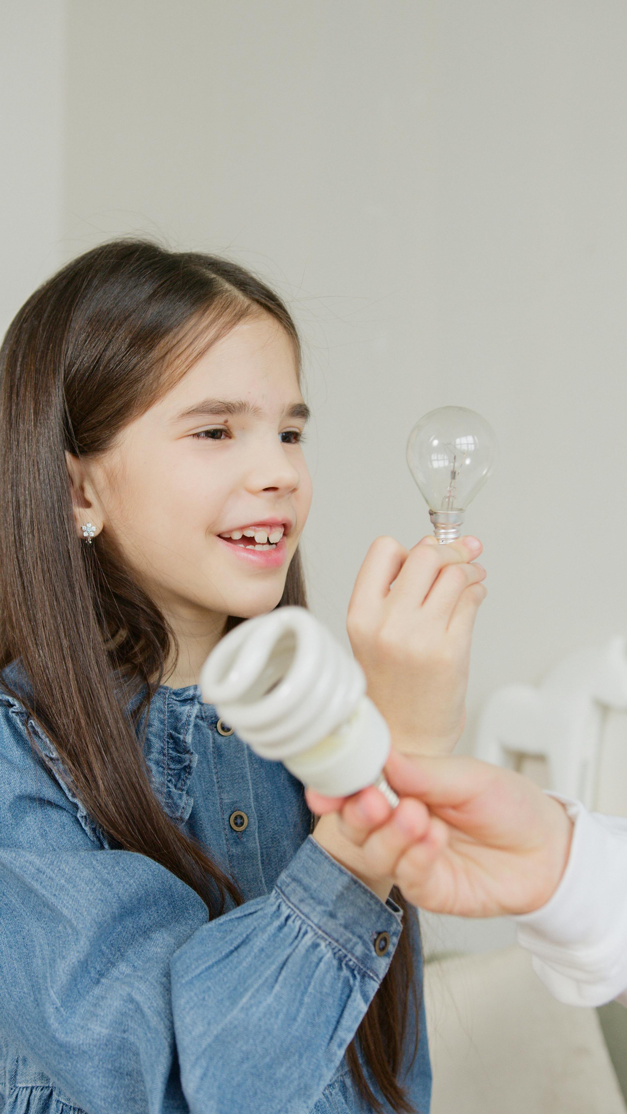 Little Girl Holding Light Bulb in front of her Face · Free Stock Photo