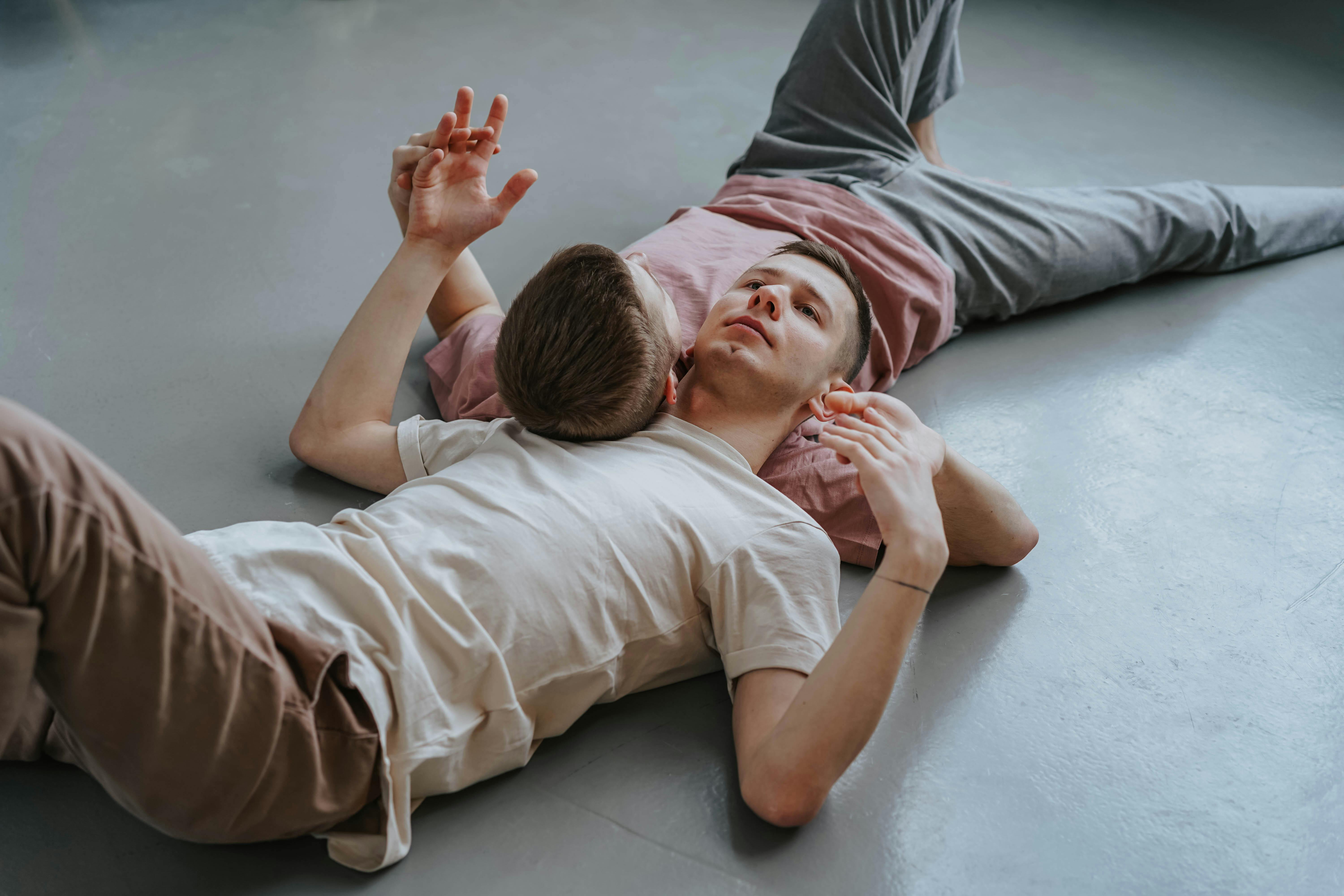 Photograph of Men Lying on a Gray Floor · Free Stock Photo