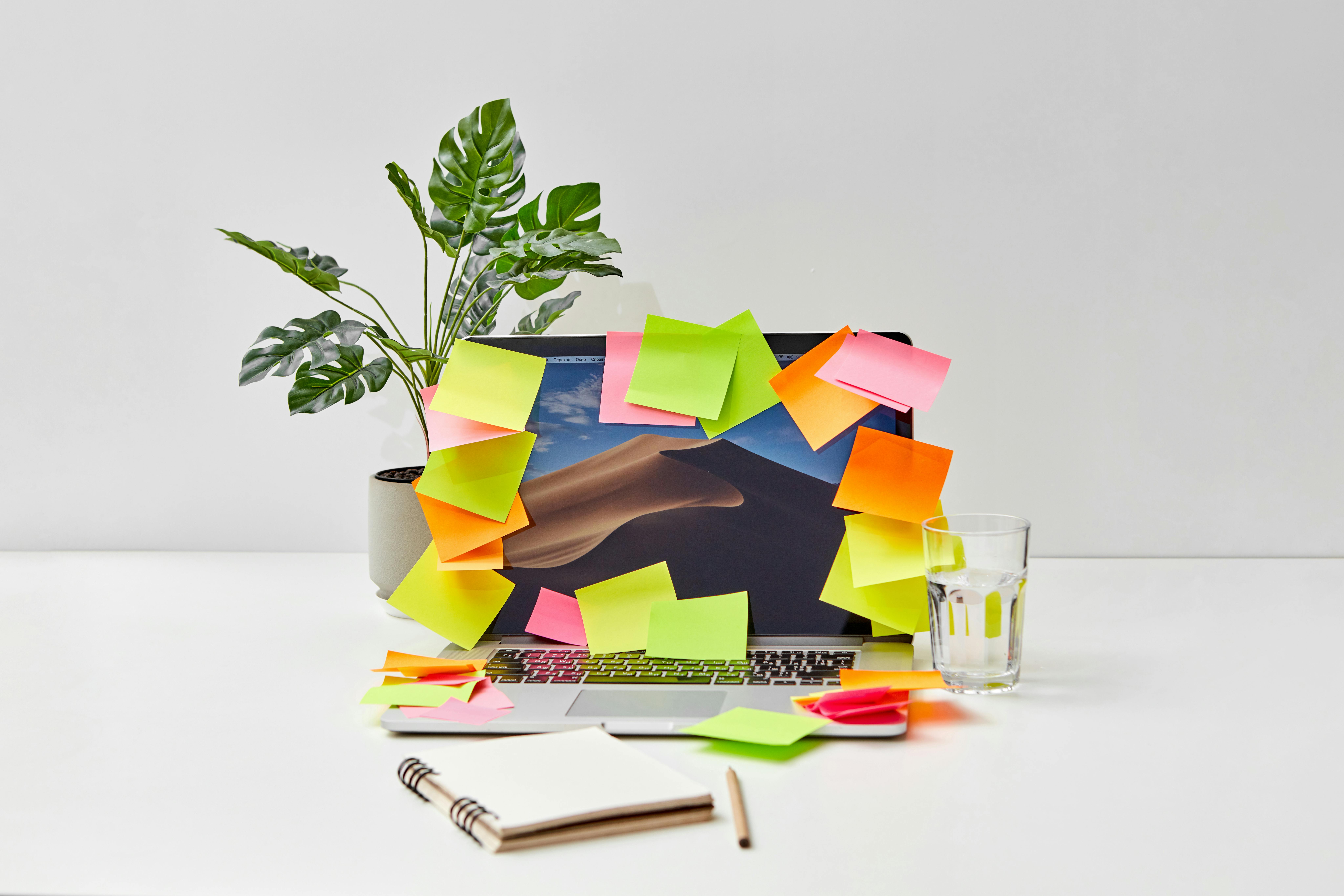 Close-Up Shot of a Laptop with Sticky Notes beside a Plant and a Glass ...