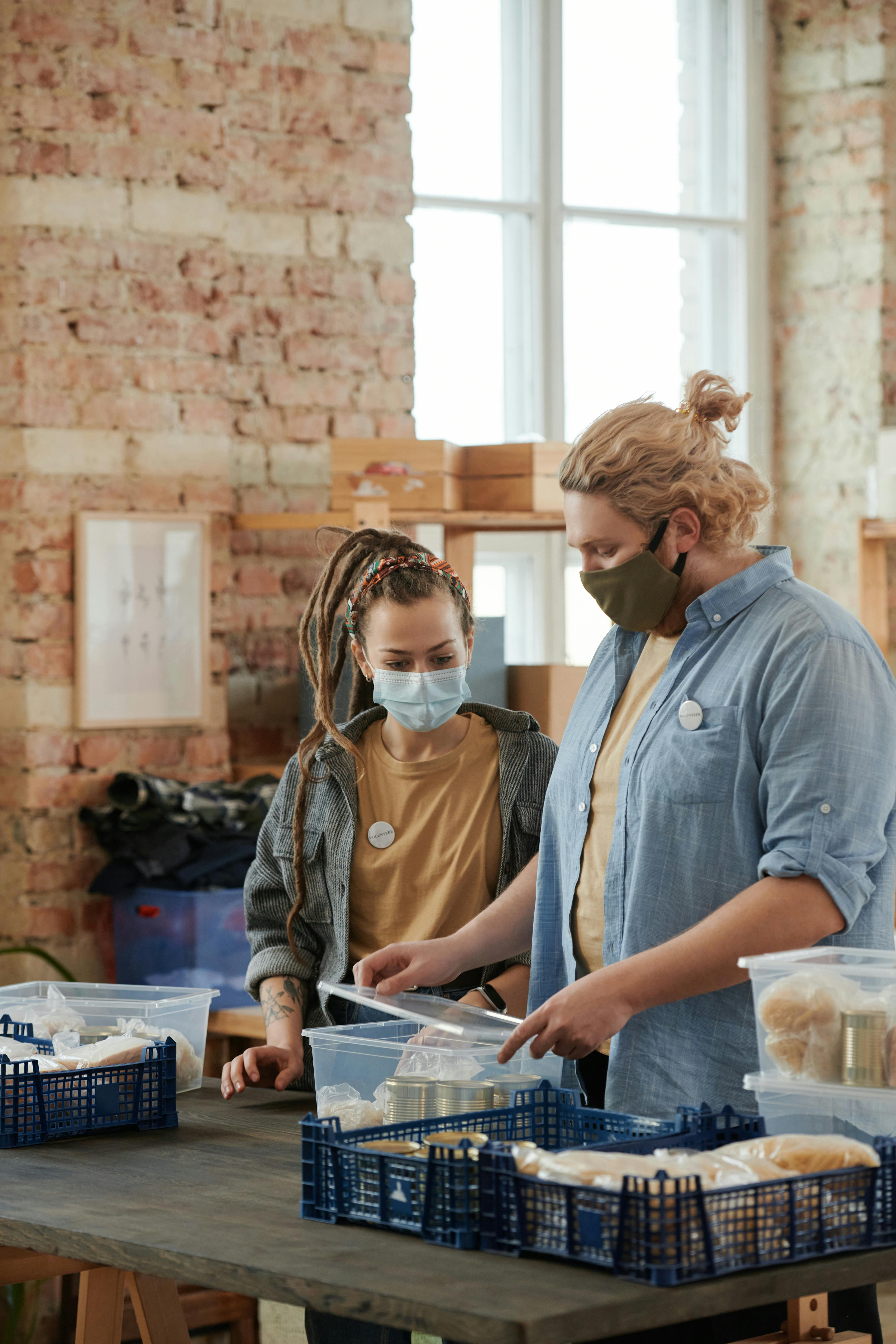 Volunteers Wearing Face Masks in front of Donations · Free Stock Photo