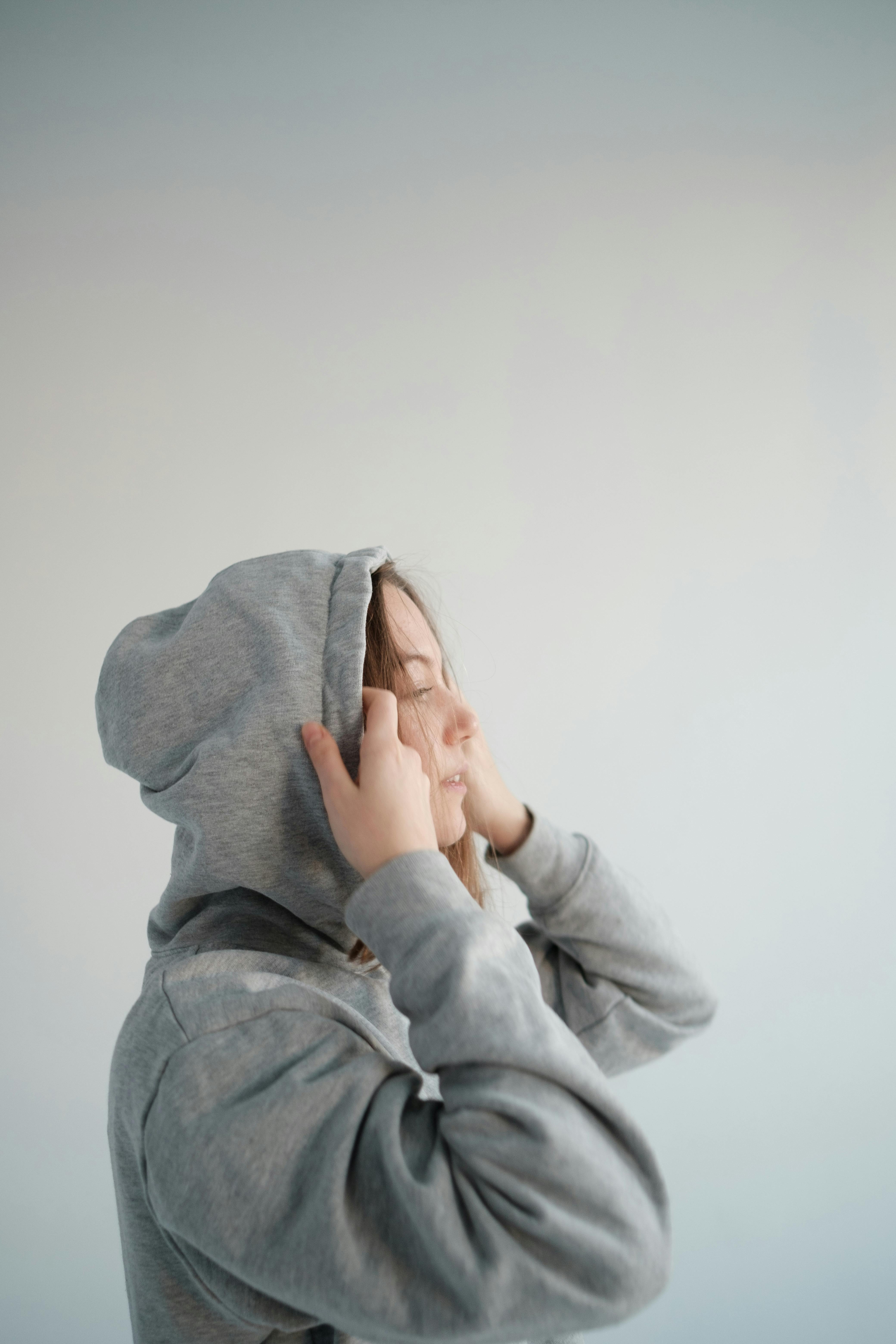 Stylish woman putting on hood in studio · Free Stock Photo