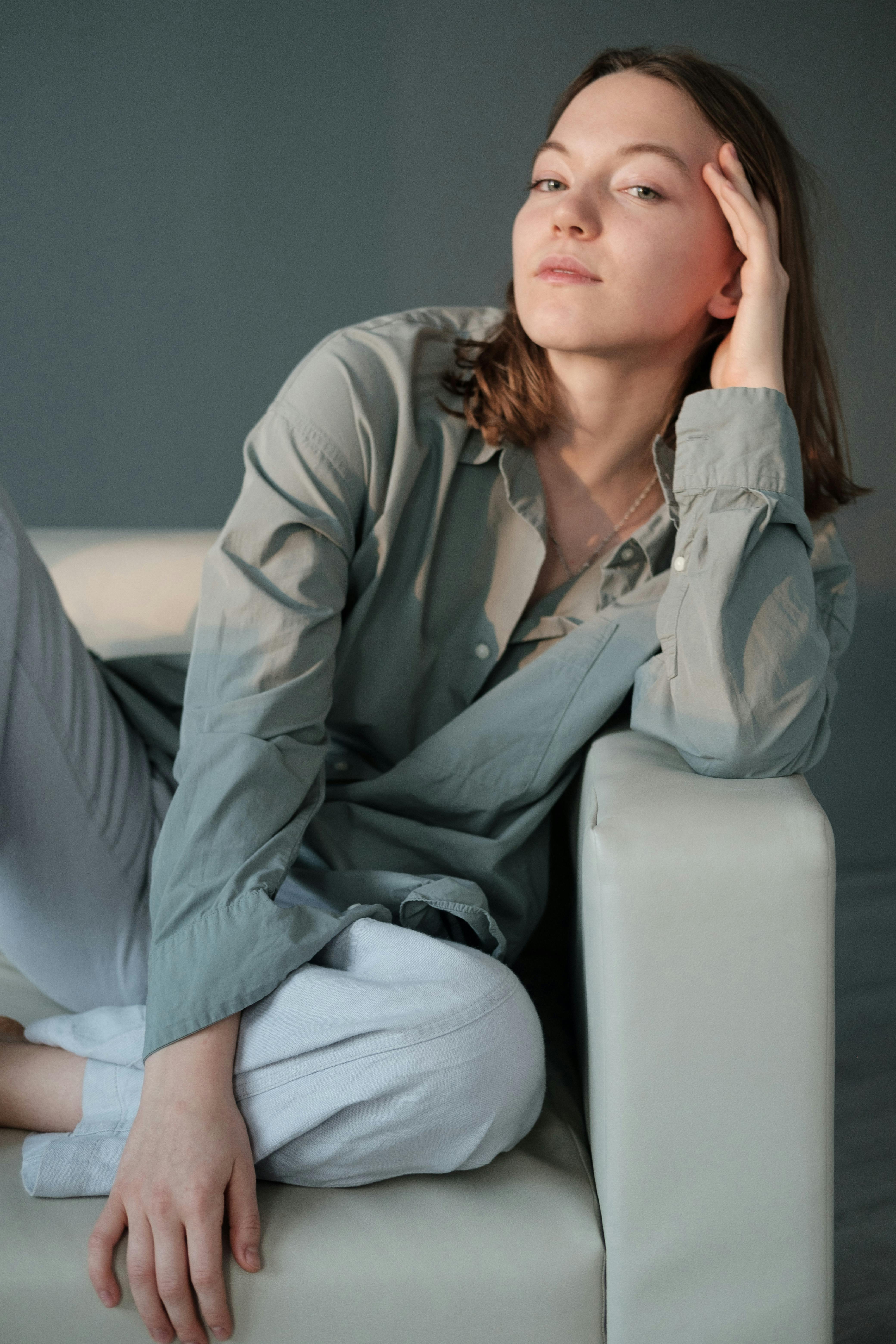 Gentle woman touching head while sitting on sofa · Free Stock Photo