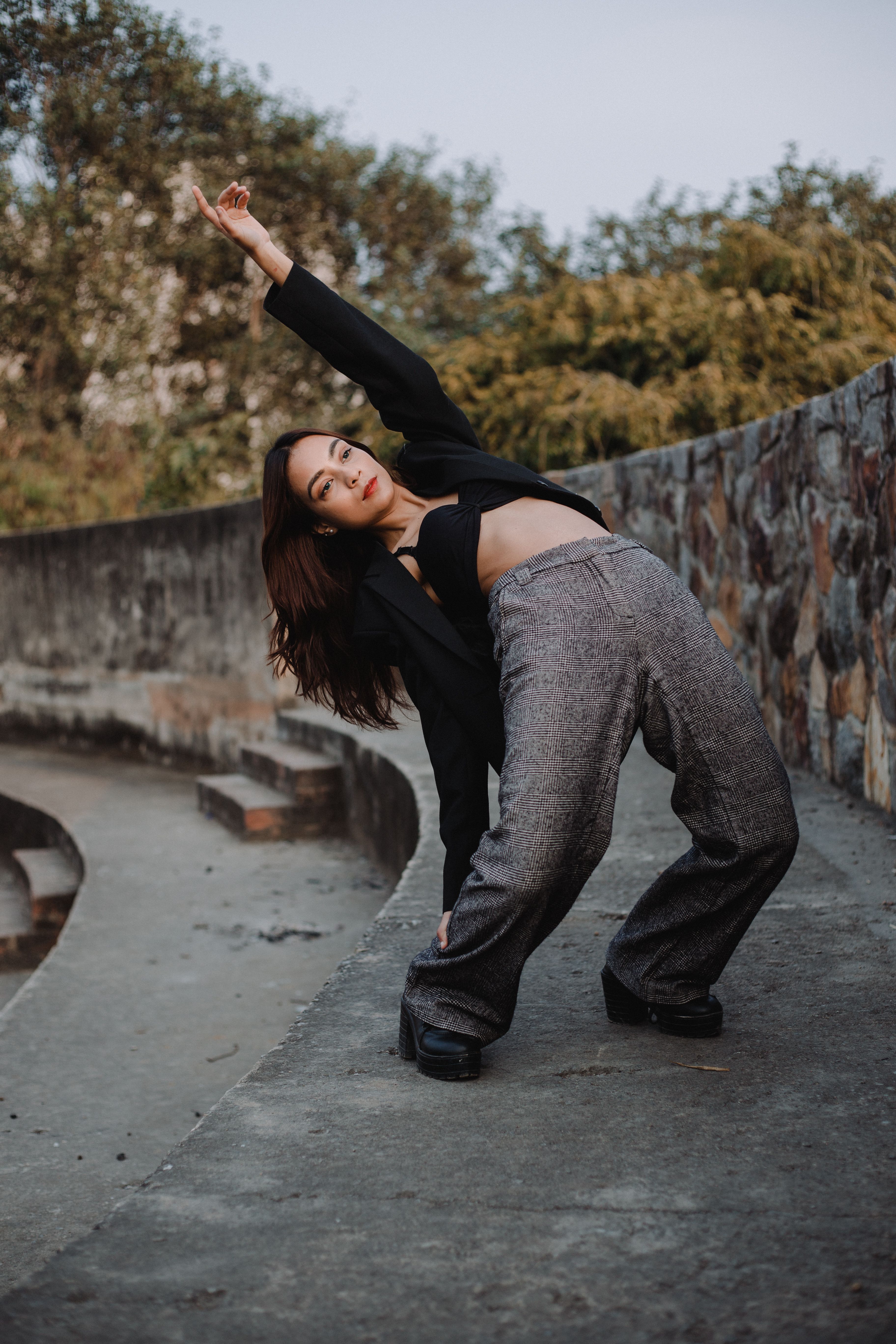 Young female model standing in bridge pose near stone fence · Free ...