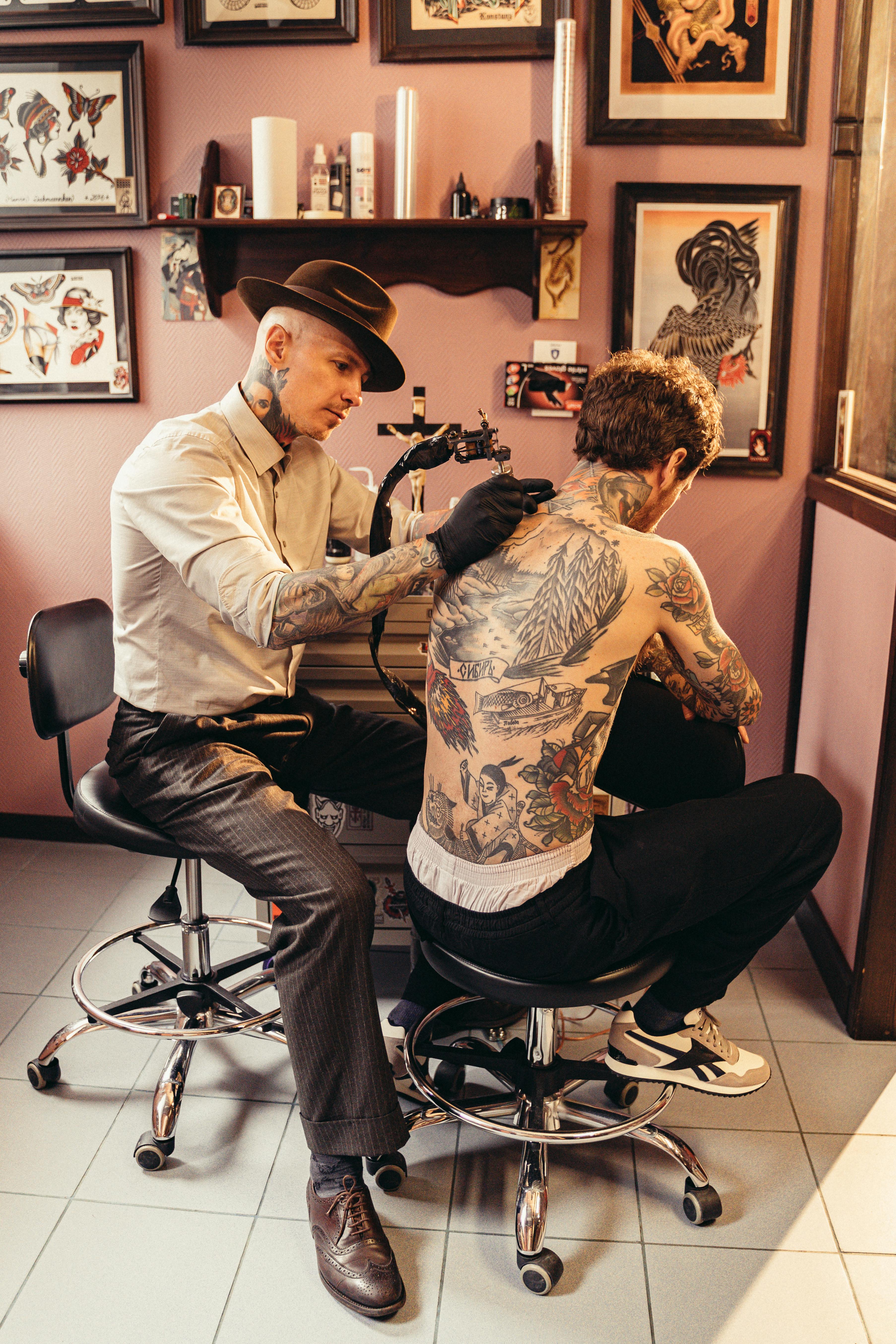 A Tattoo Artist Working on a Client · Free Stock Photo