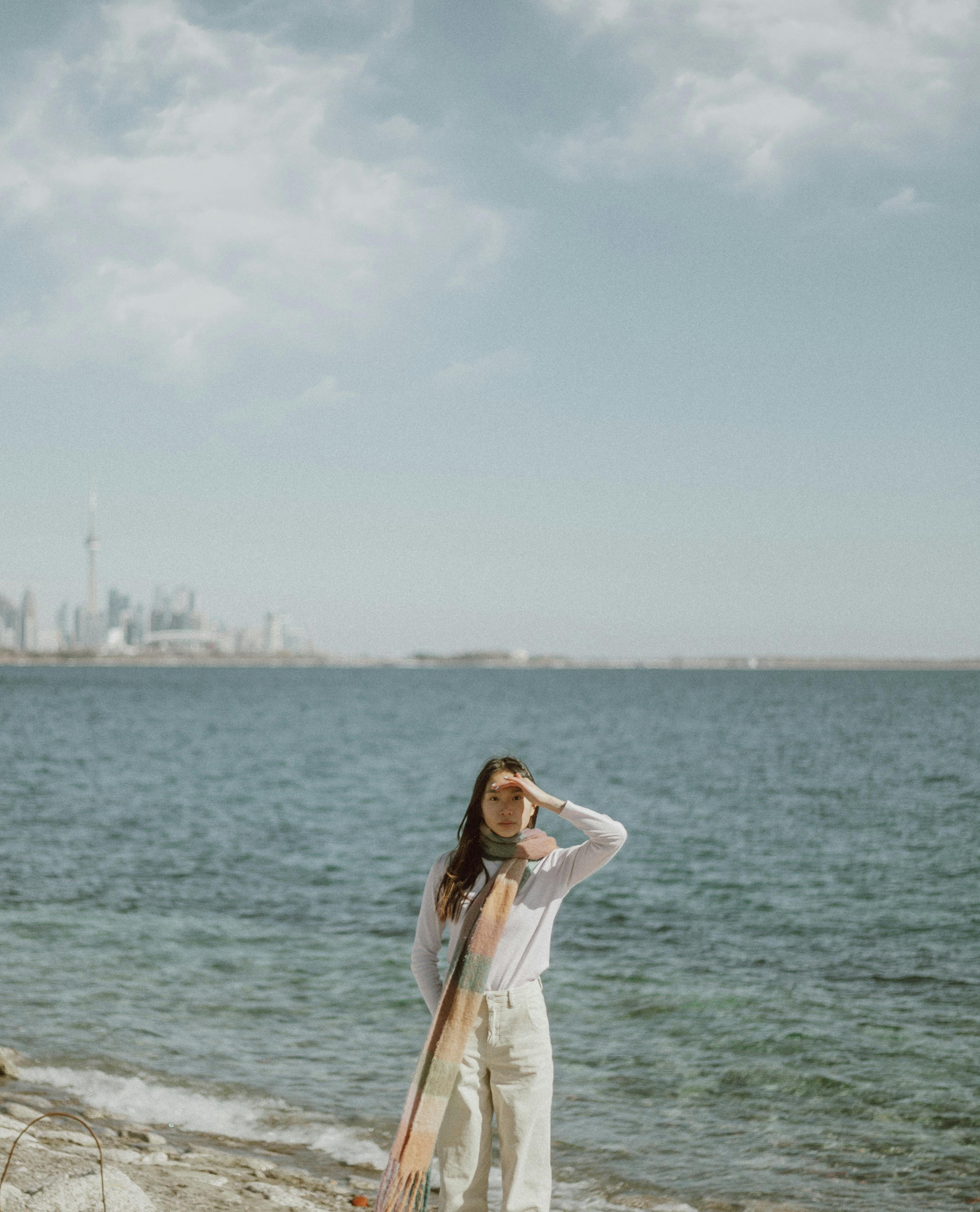Ethnic female covering face from sunlight standing on shore · Free ...