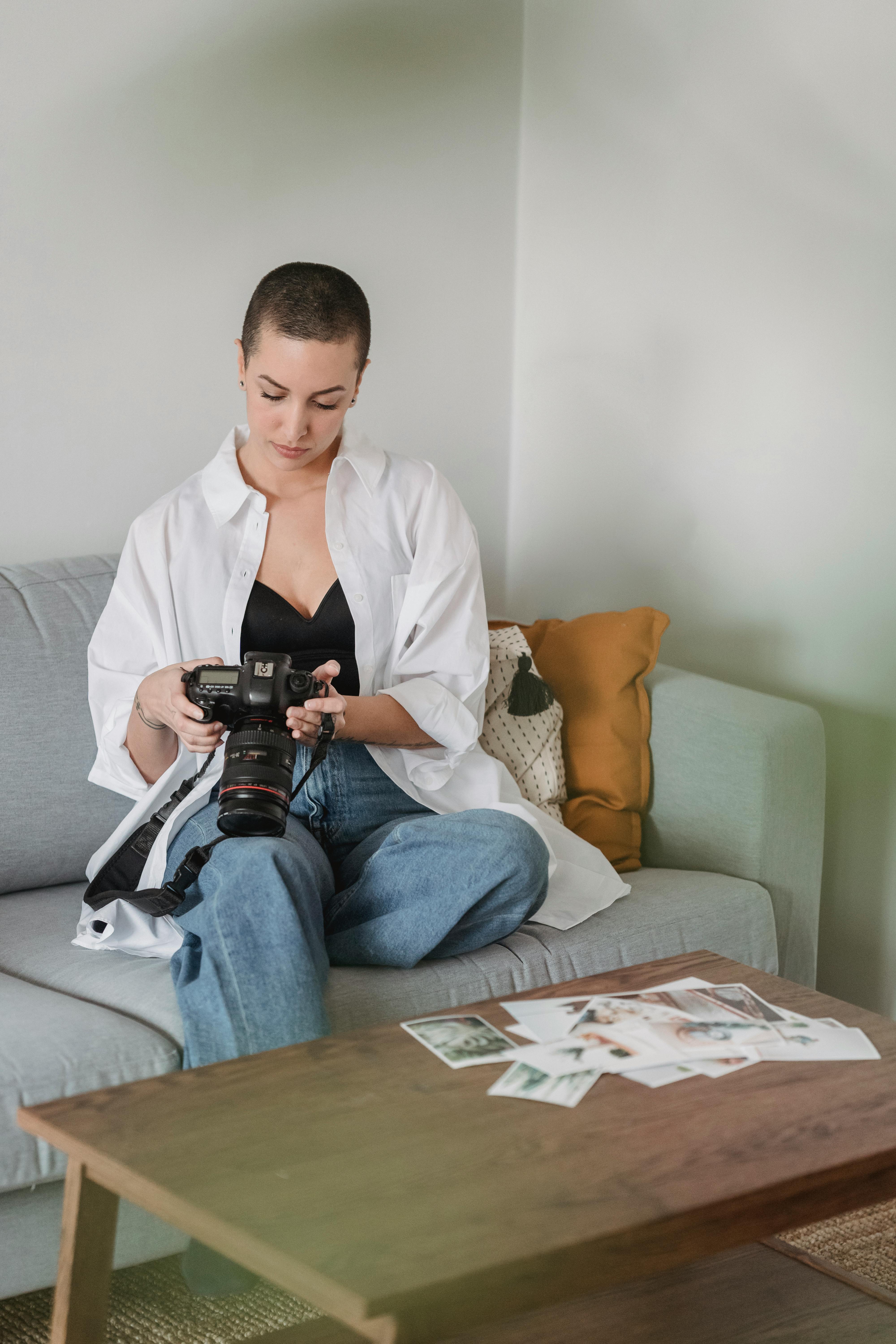 Serious woman sitting on sofa and renewing photos on camera · Free ...
