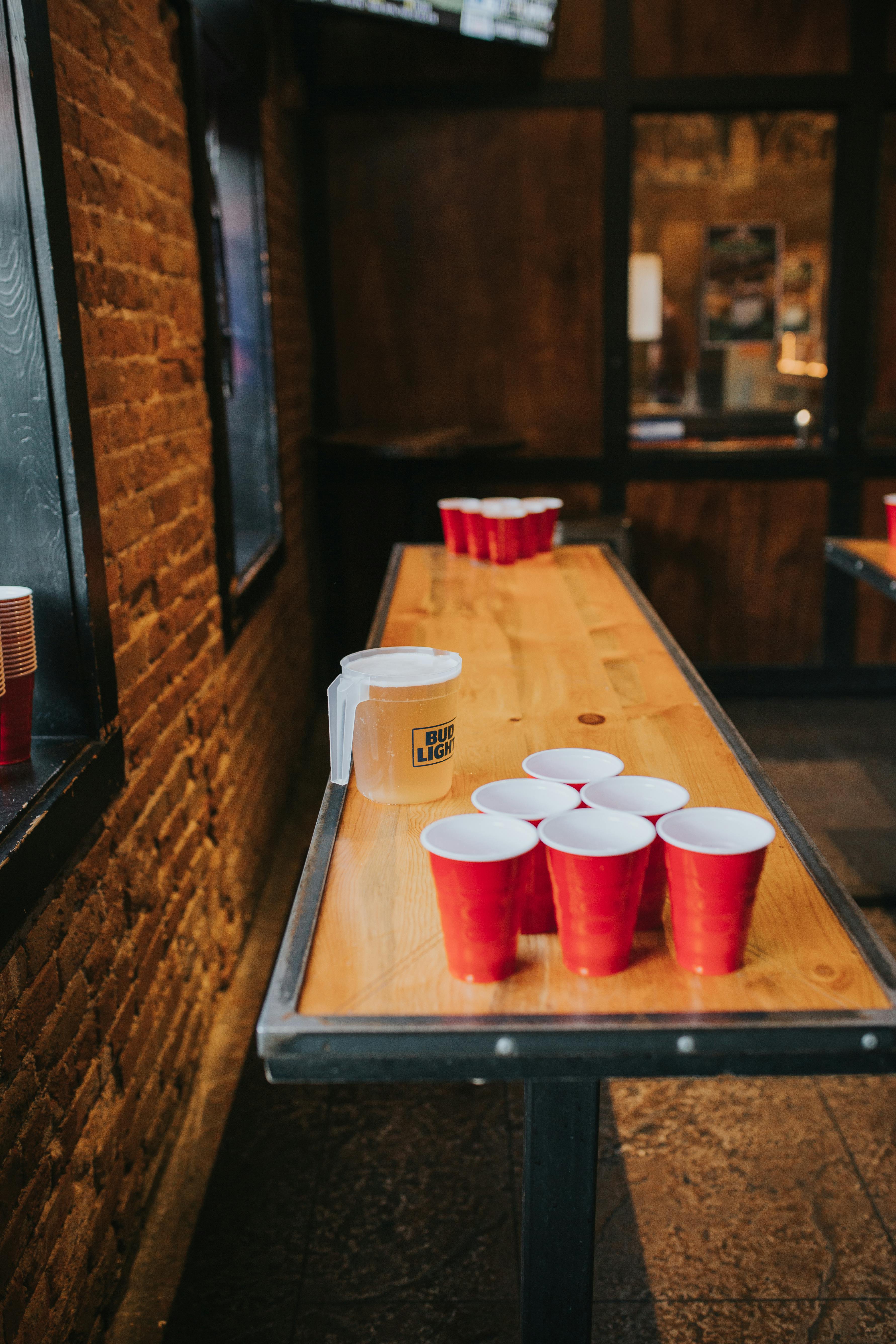 Red Plastic Cups and Pitcher of Beer on Brown Wooden Table · Free Stock ...