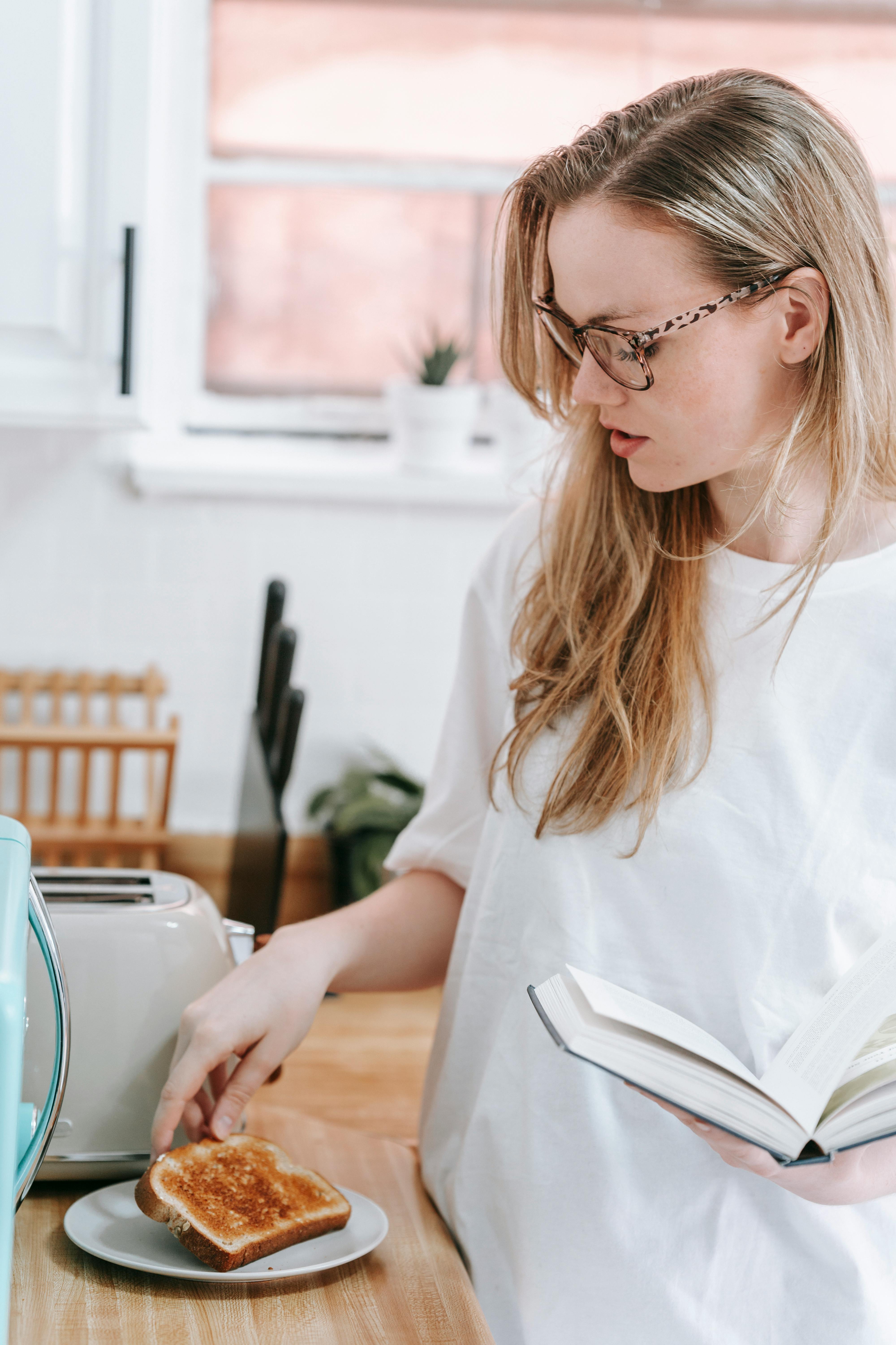 Young woman with book making toast · Free Stock Photo