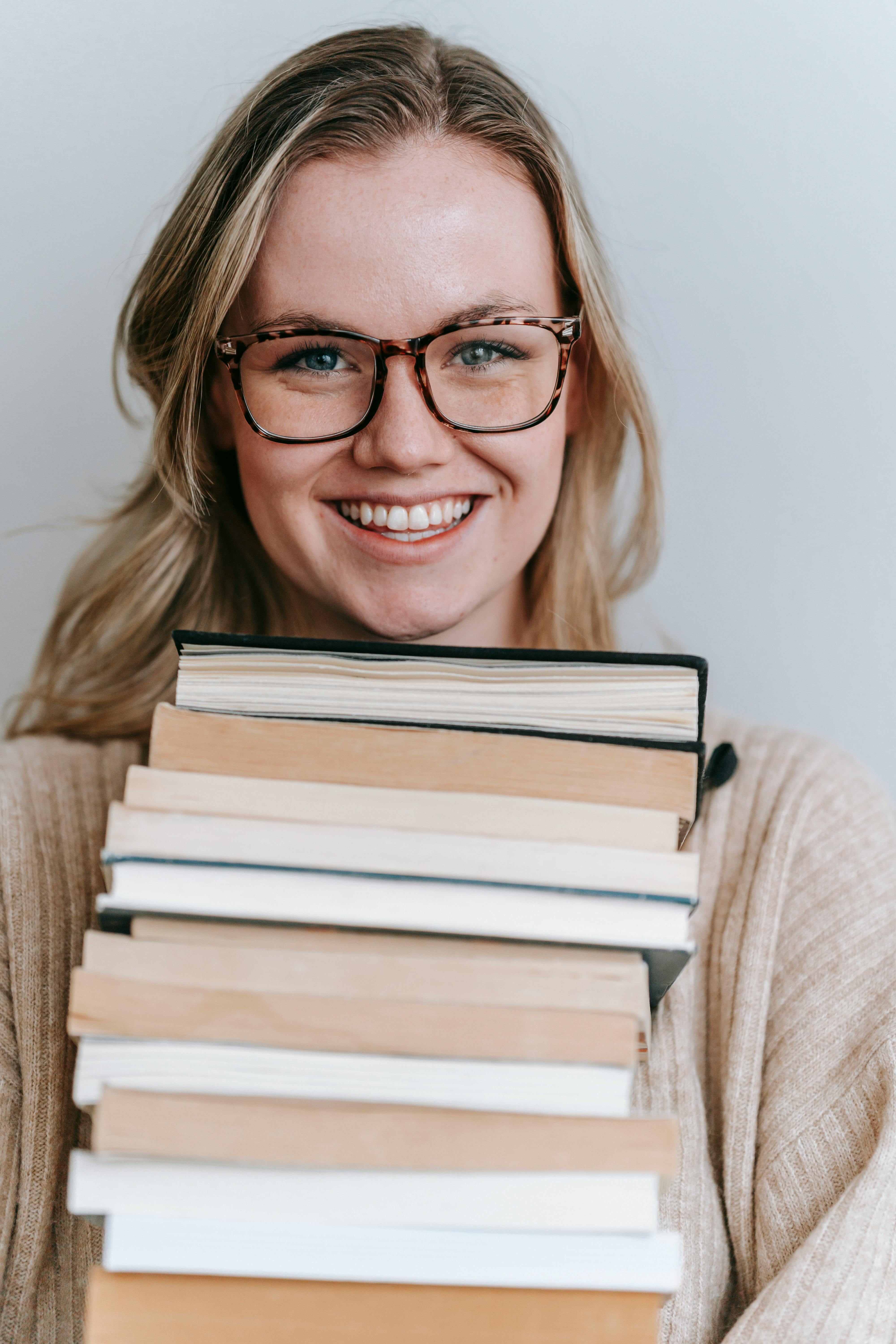 A Pretty Woman with a Stack of Books · Free Stock Photo