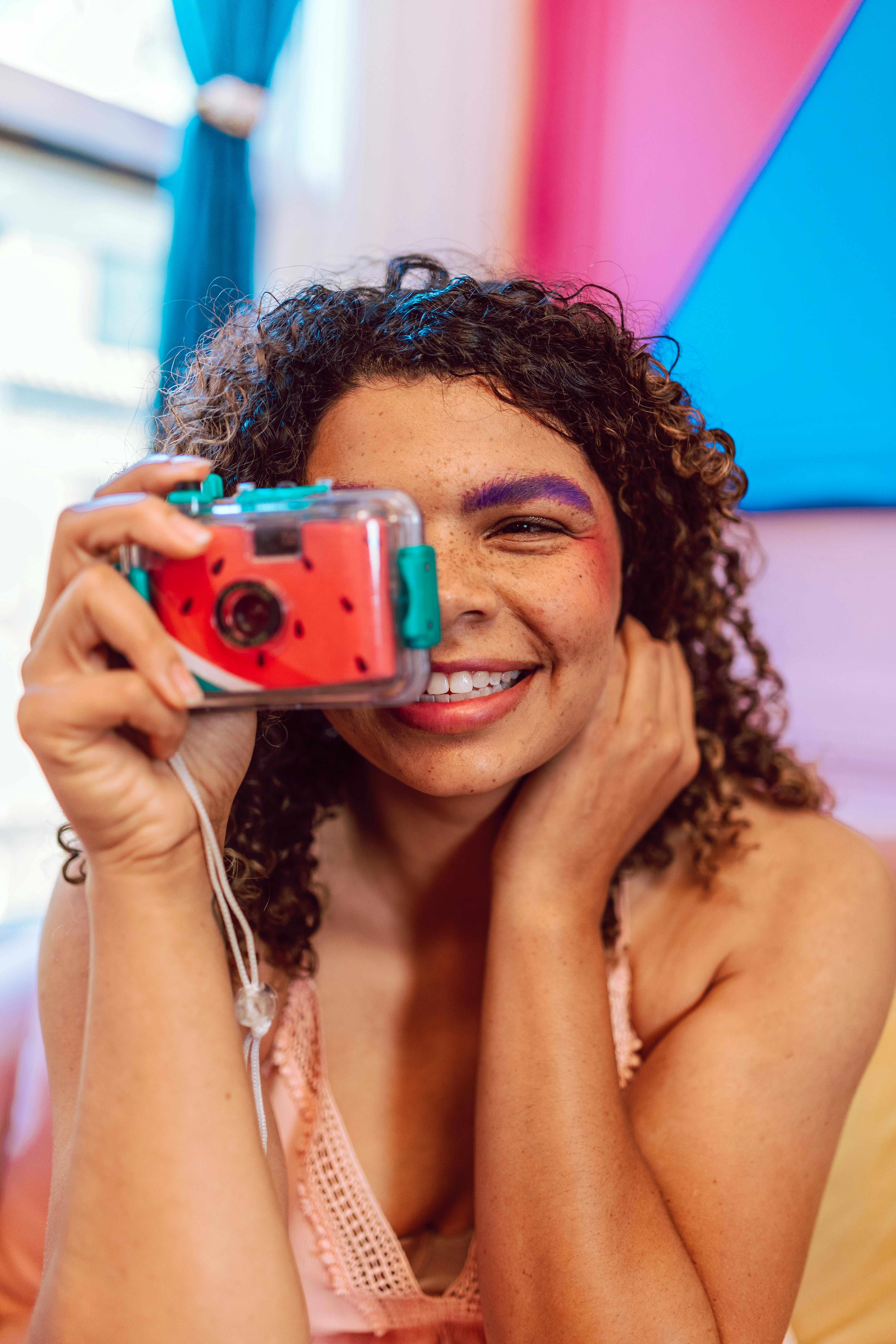 Woman with Curly Hair Using a Camera · Free Stock Photo