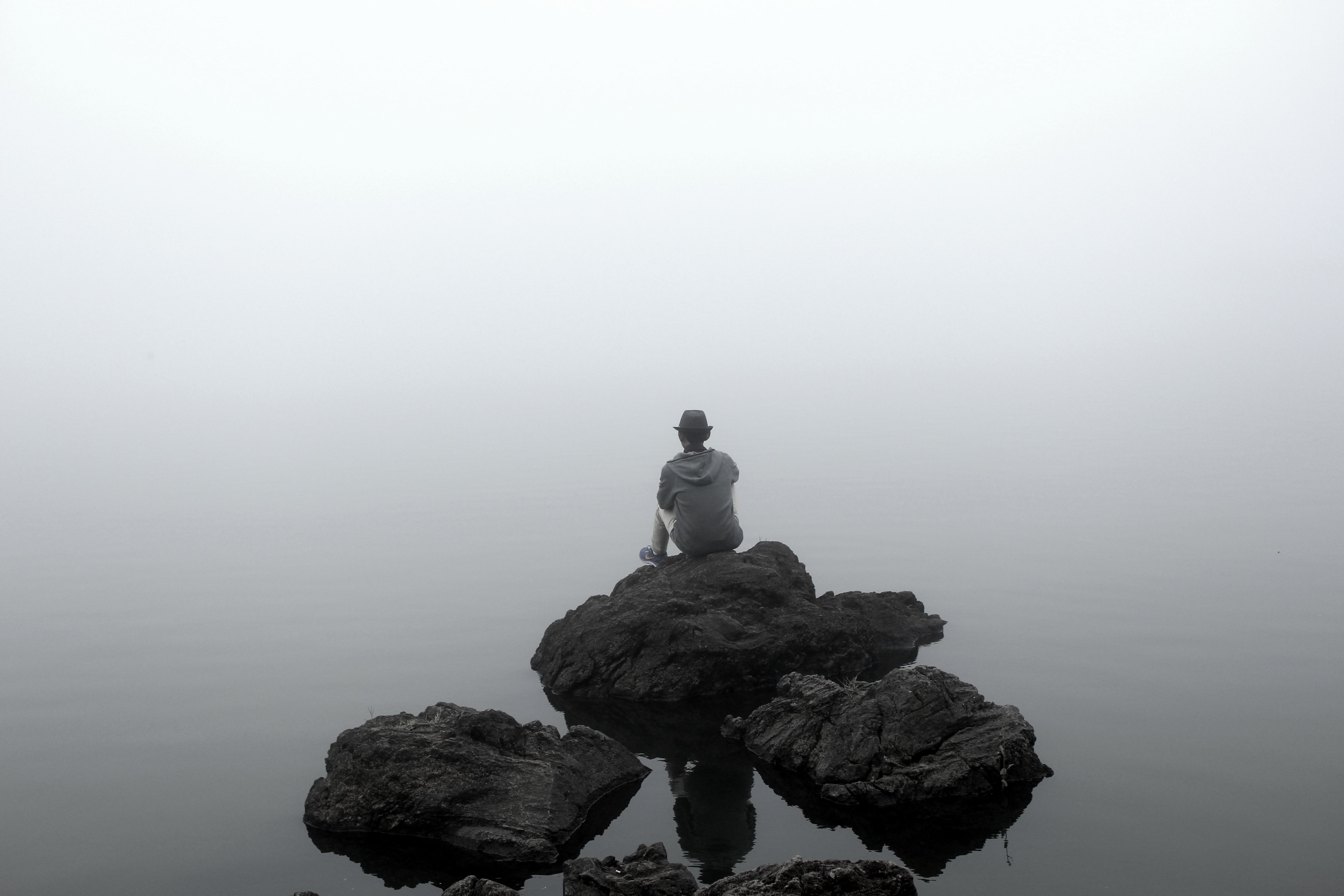 A Man Sitting on the Rock Formation on the Lake · Free Stock Photo