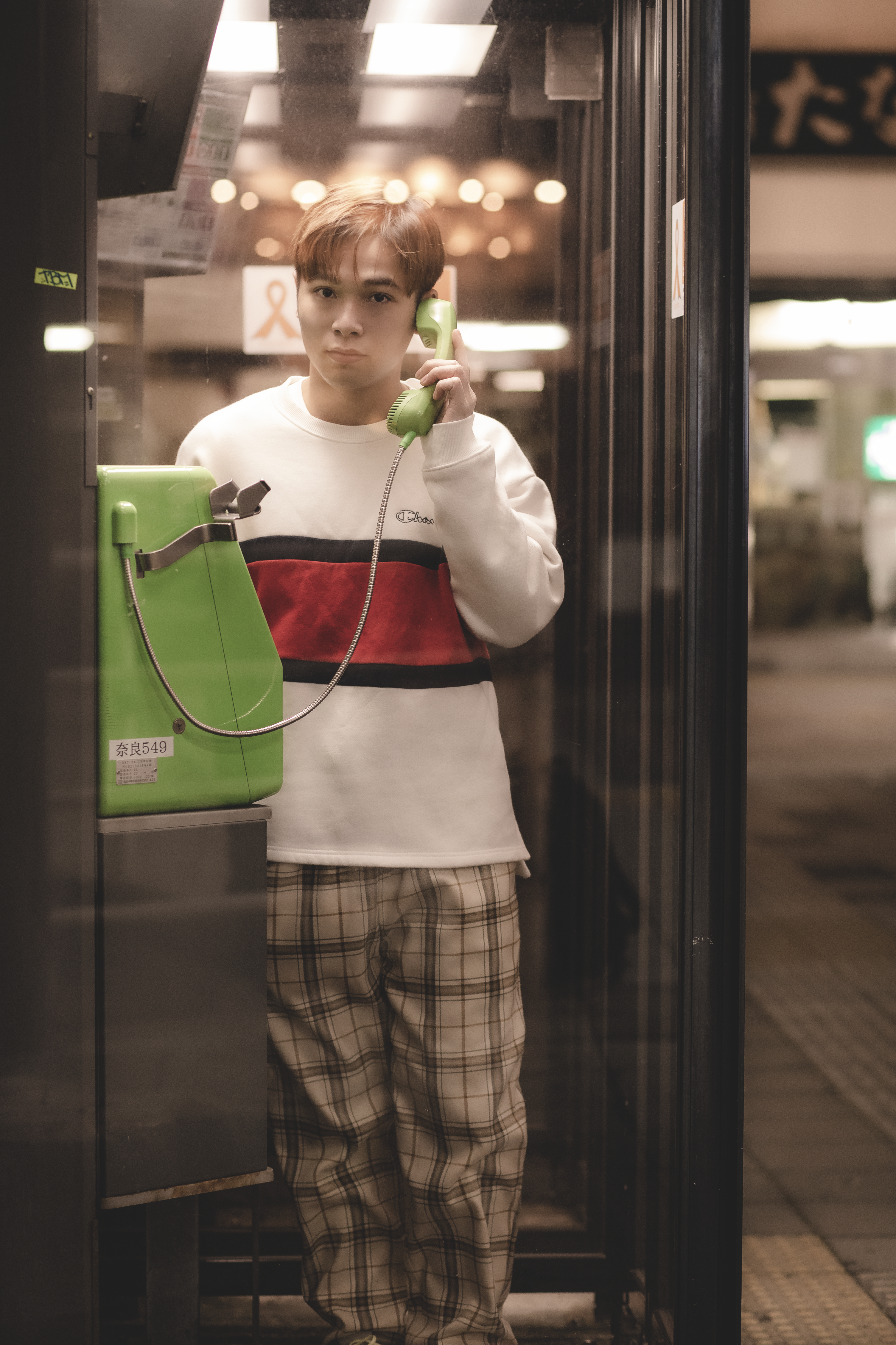 Young Man Using a Public Telephone in a Booth · Free Stock Photo