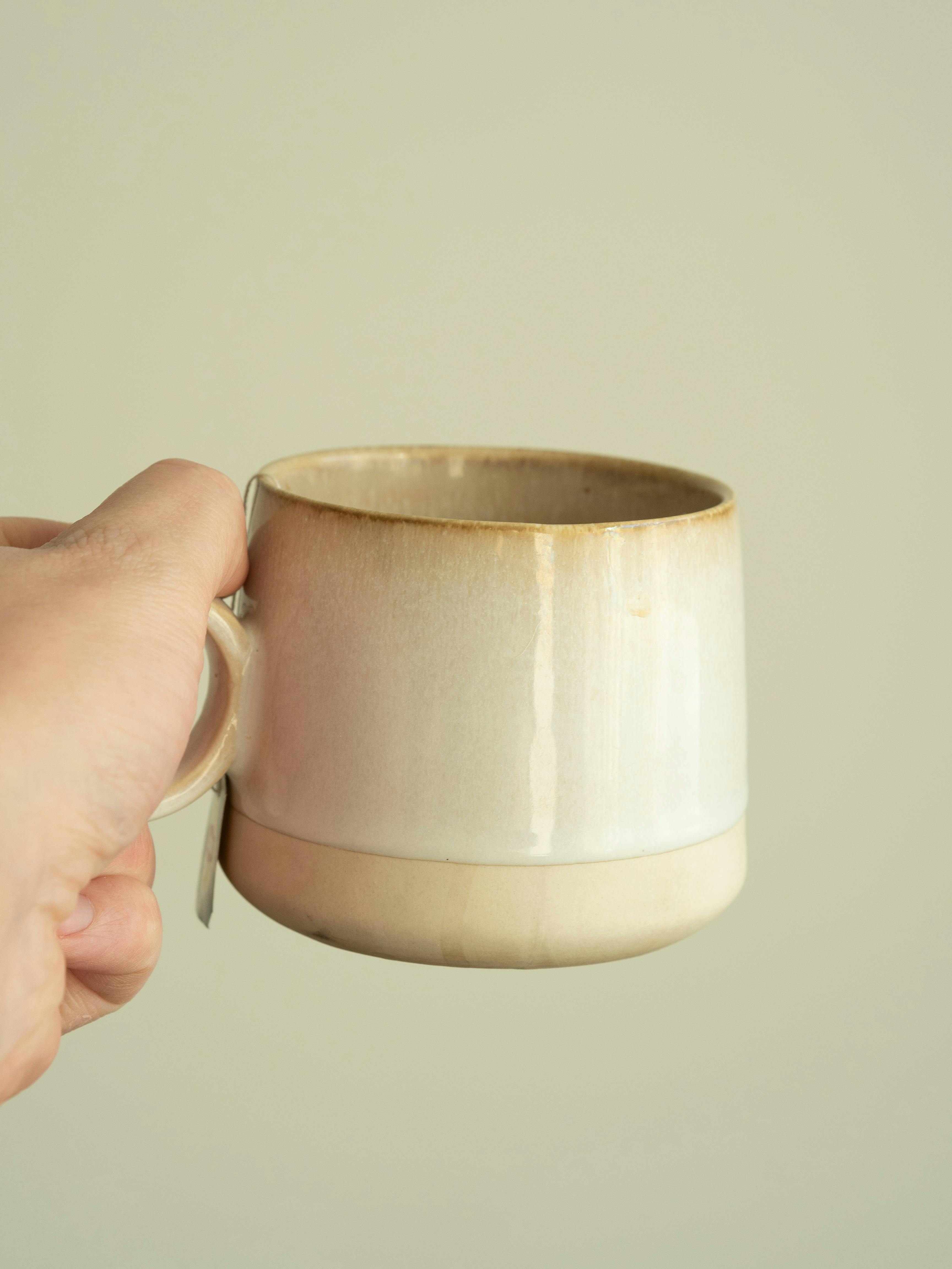Crop person taking tea mug from chair covered with carpet · Free Stock ...