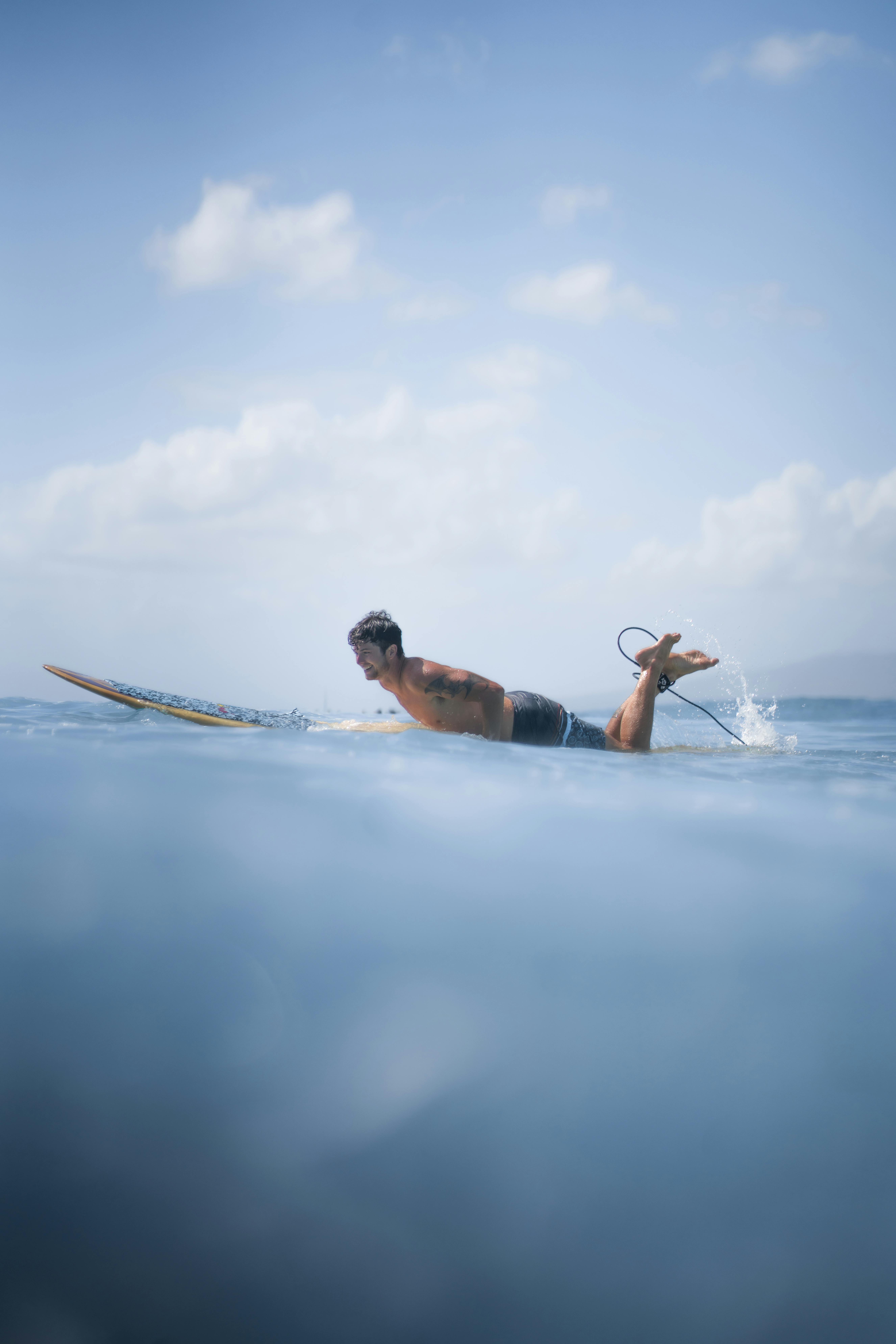 Surfer lying on board floating on water · Free Stock Photo