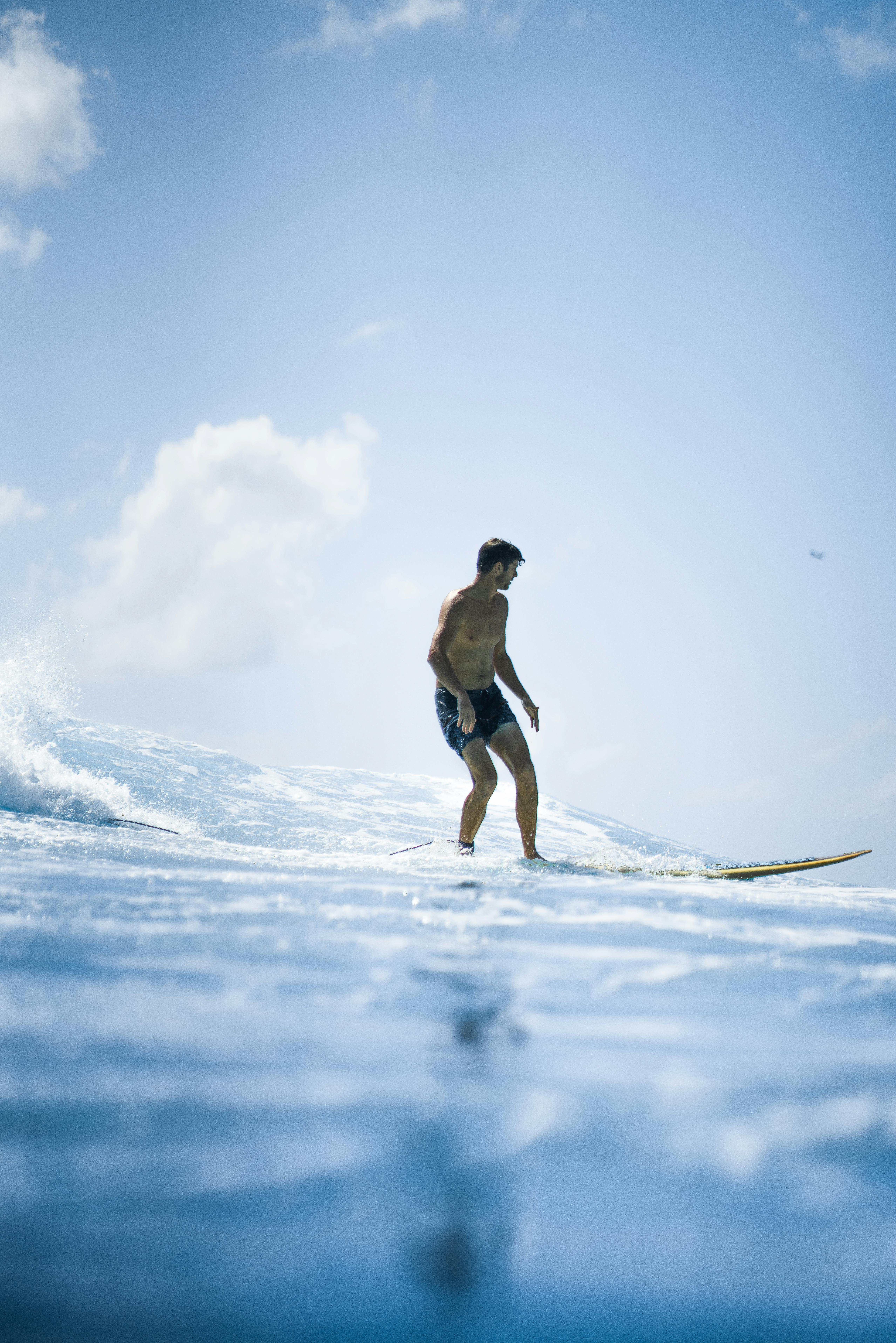Athletic man riding surfboard in sea · Free Stock Photo