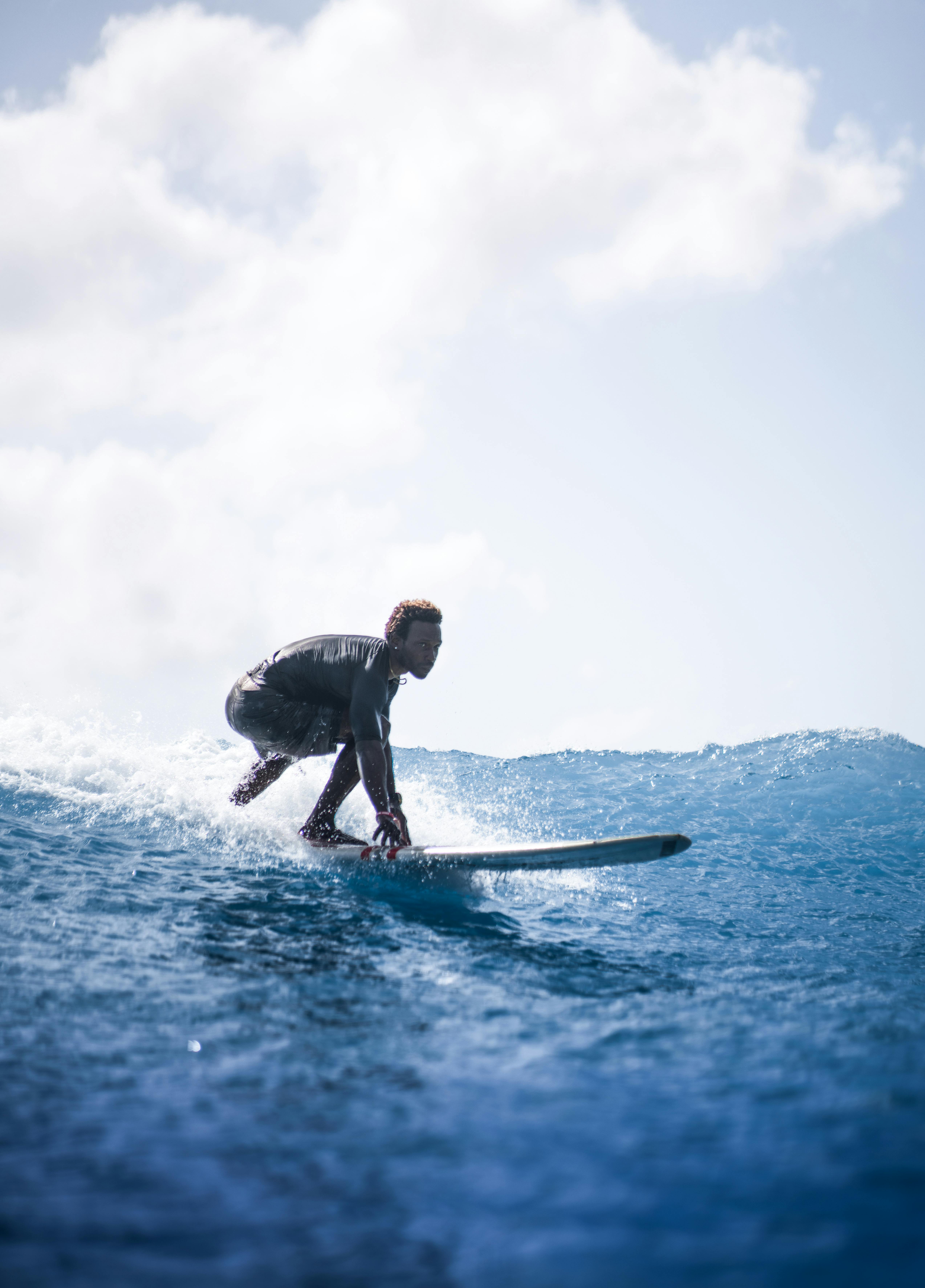Man riding surfboard in wavy ocean · Free Stock Photo