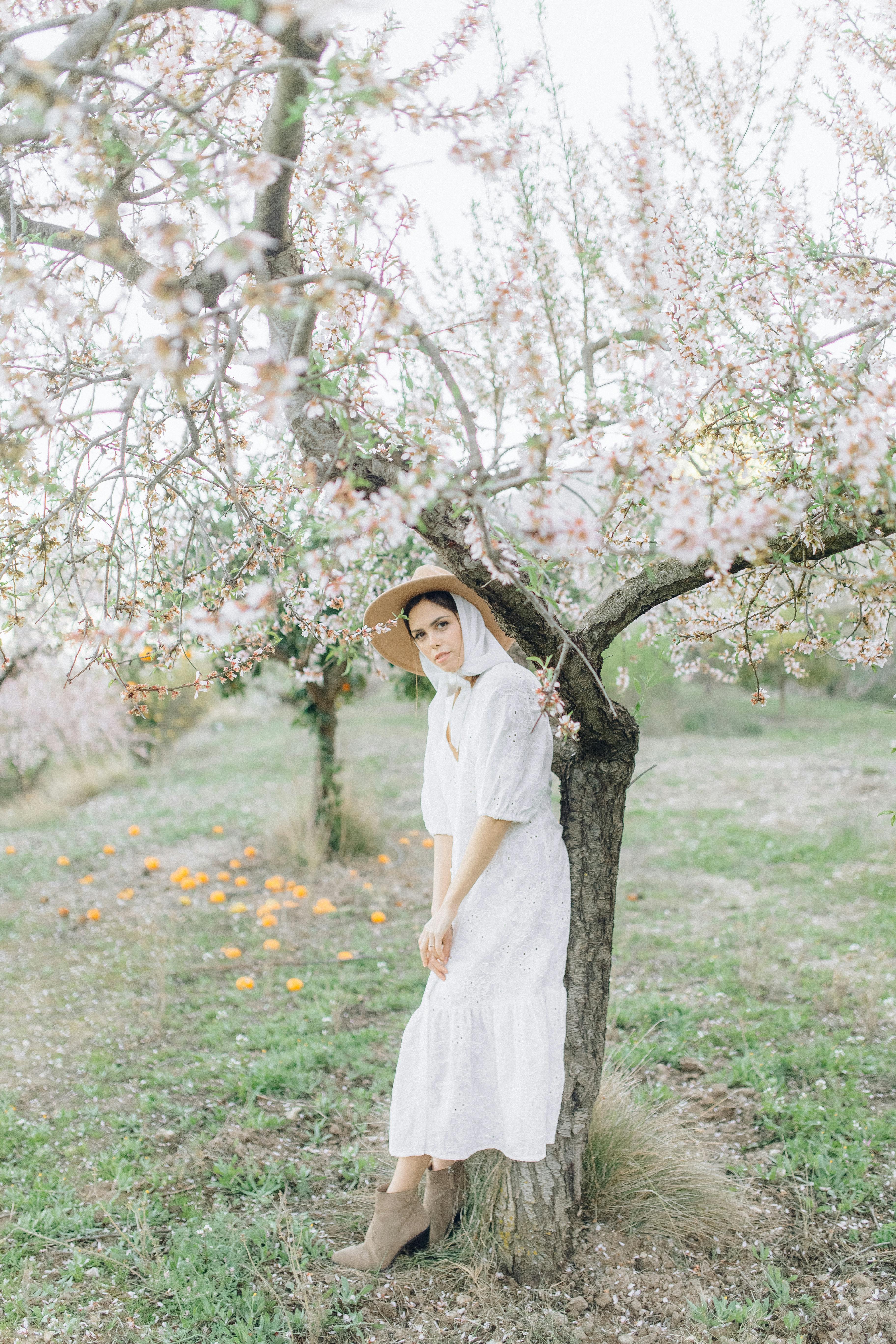 Woman in White Dress and Brown Hat Leaning on Tree · Free Stock Photo