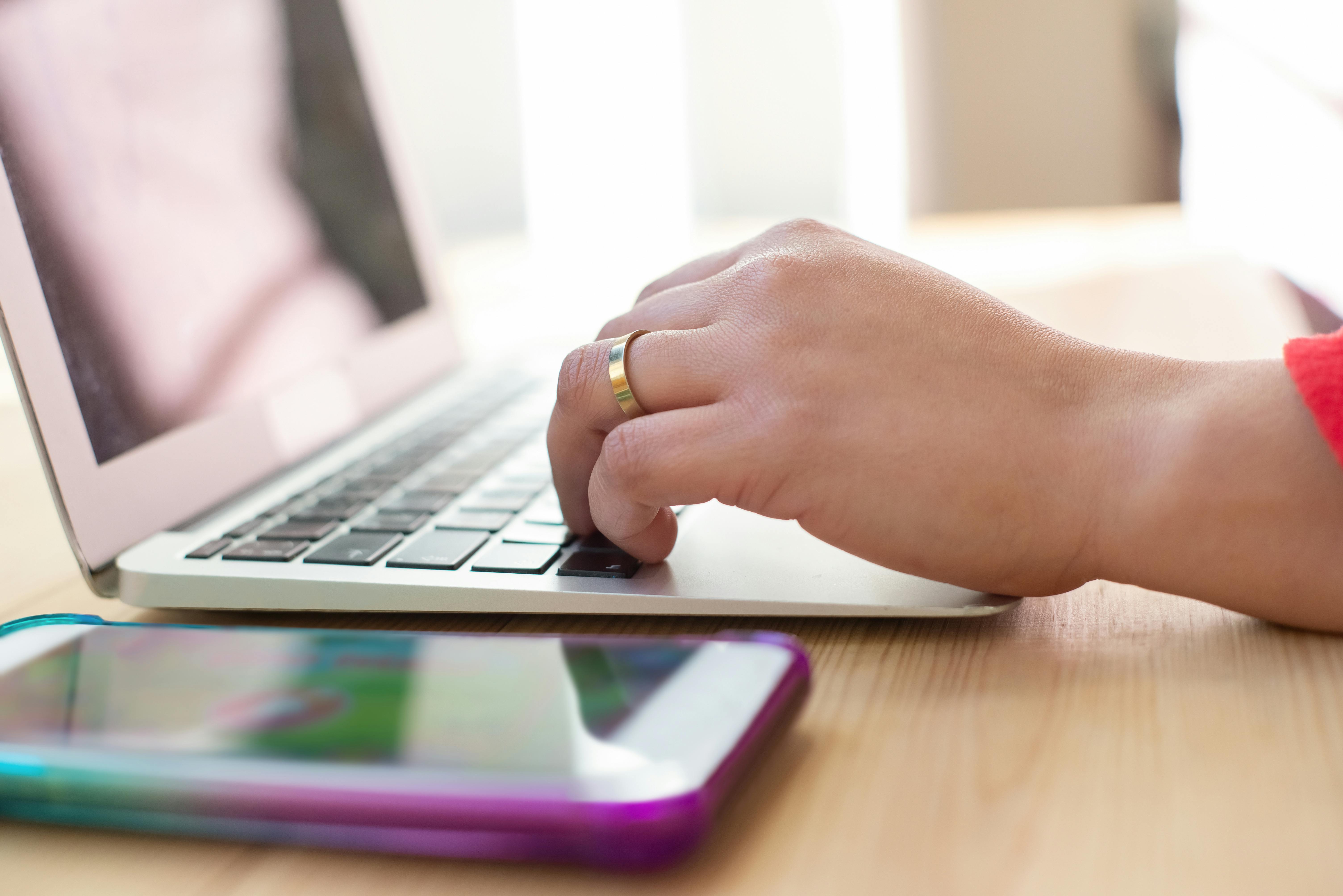 Hand Resting on a Silver Laptop · Free Stock Photo