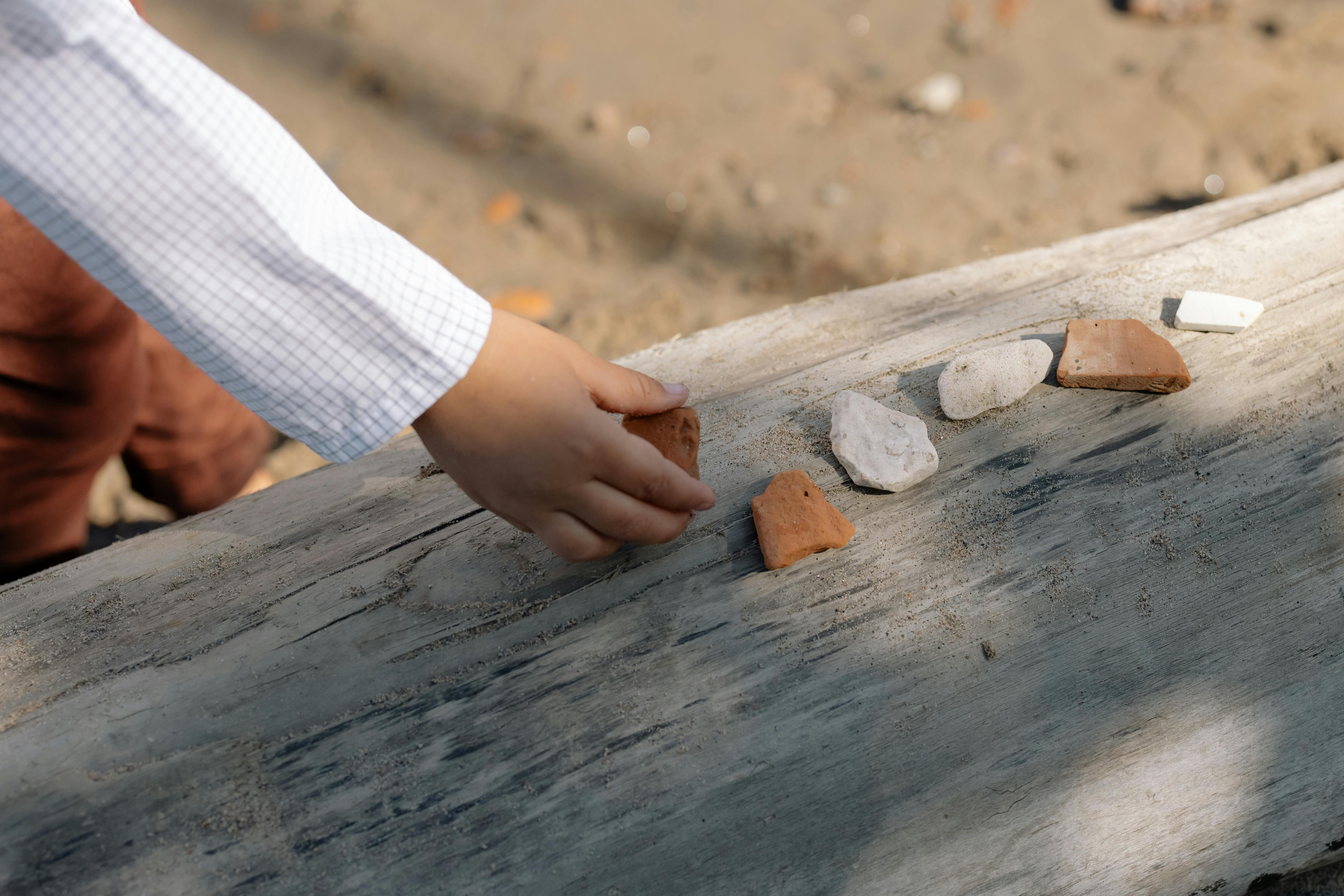 Close-Up Shot of Person Putting Rocks on Wooden Surface · Free Stock Photo