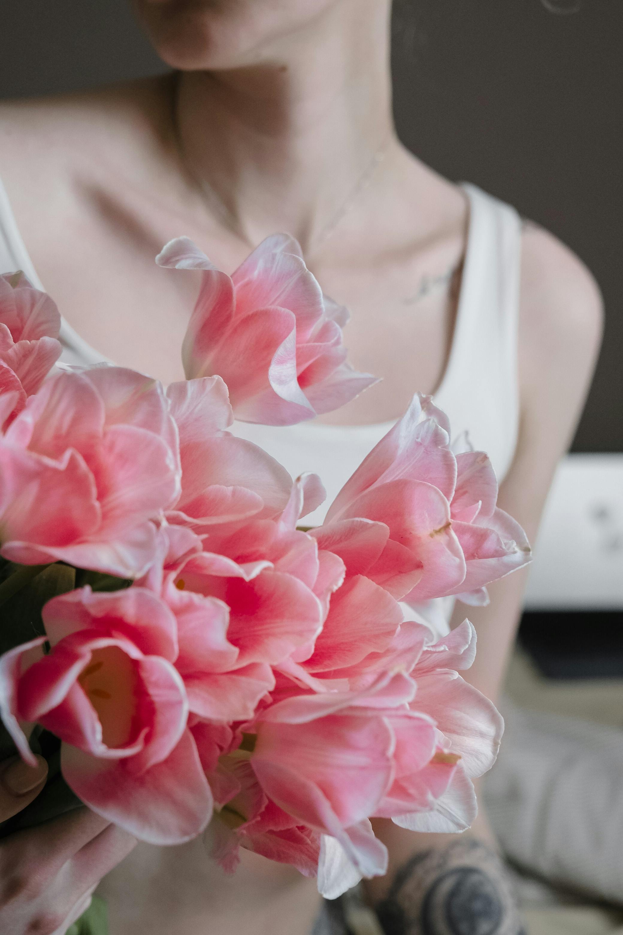 A Woman in White Tank Top Holding Pink Rose Bouquet · Free Stock Photo