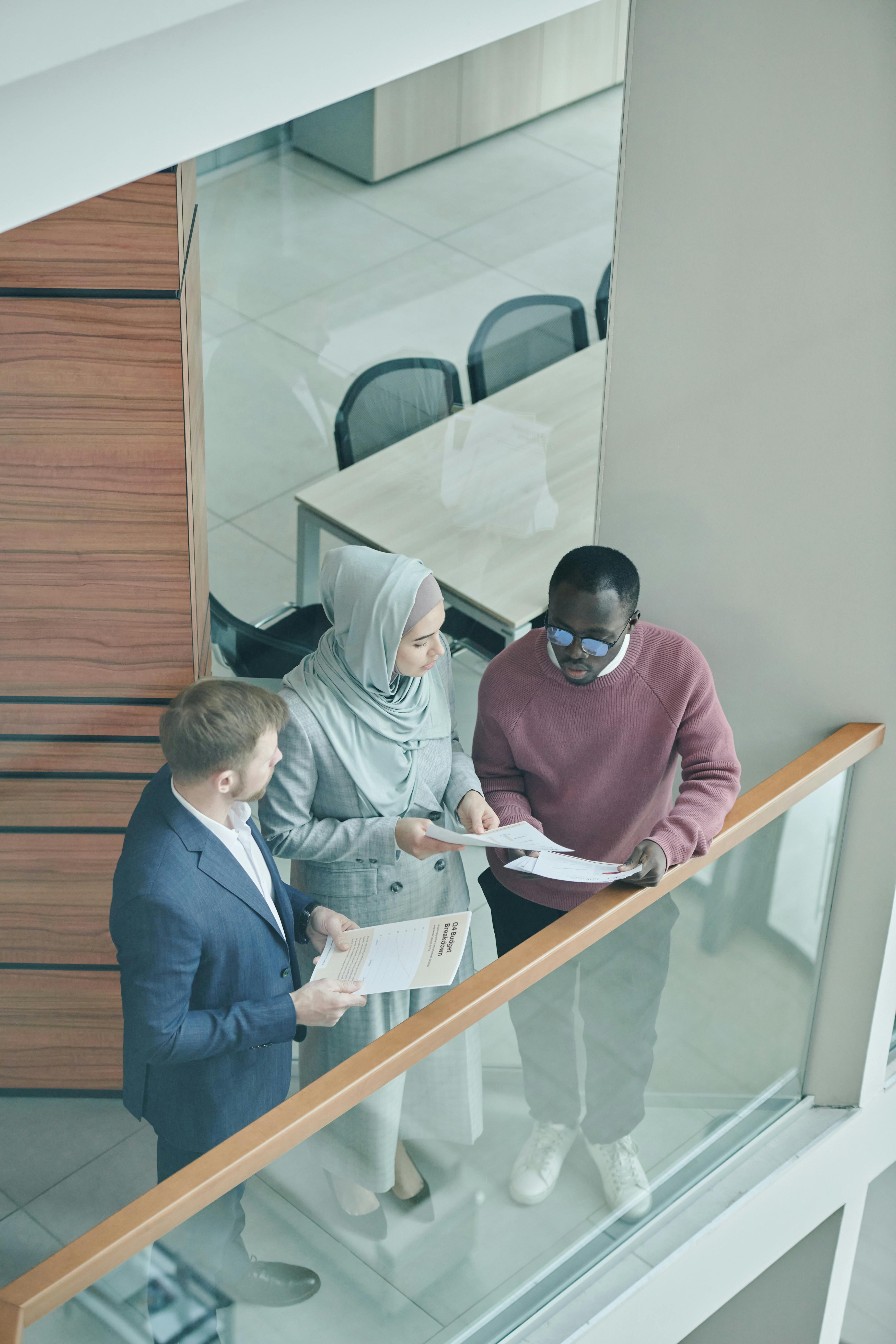 Three People Holding Documents and Discussing · Free Stock Photo