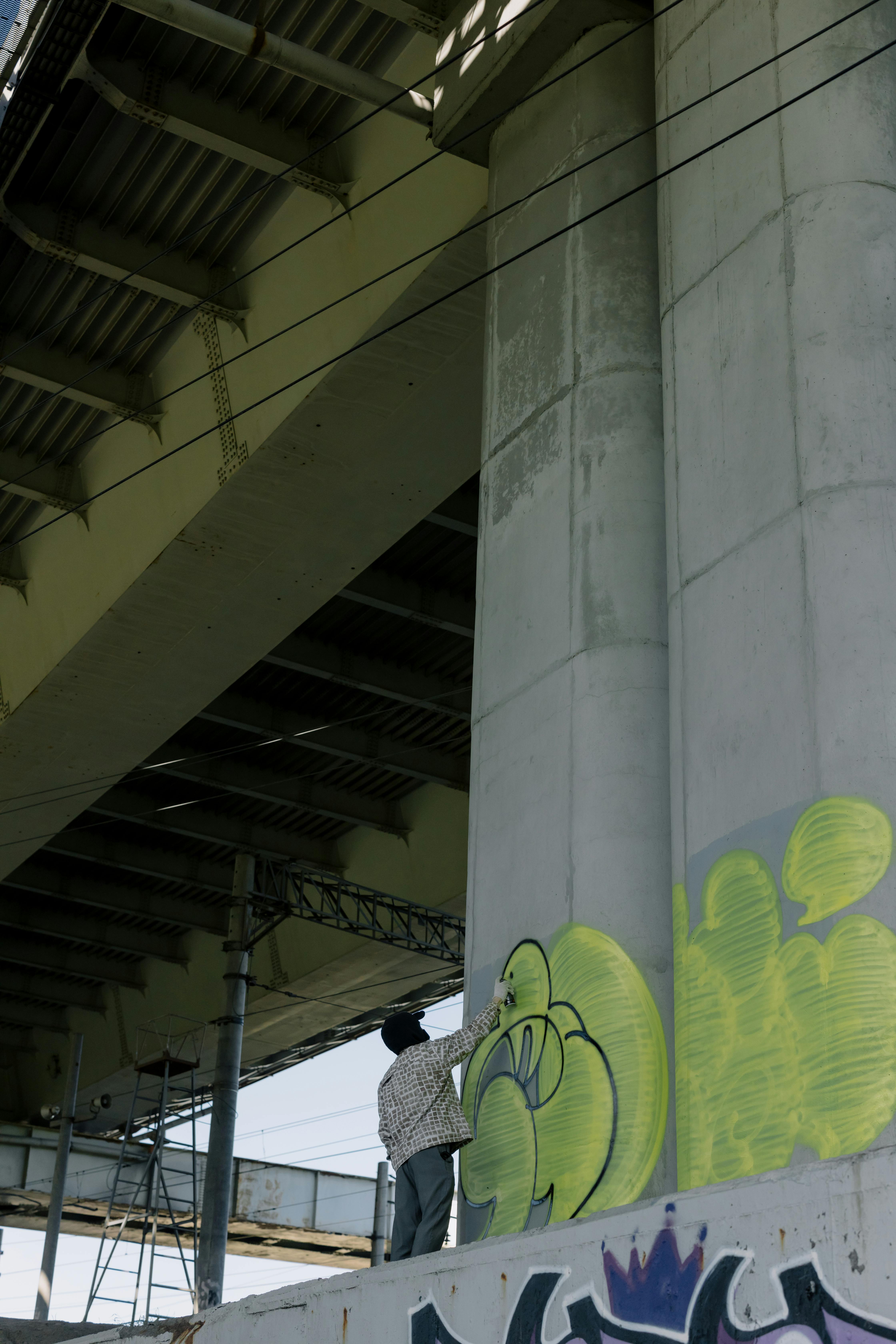 A Person Spray Painting under the Bridge · Free Stock Photo