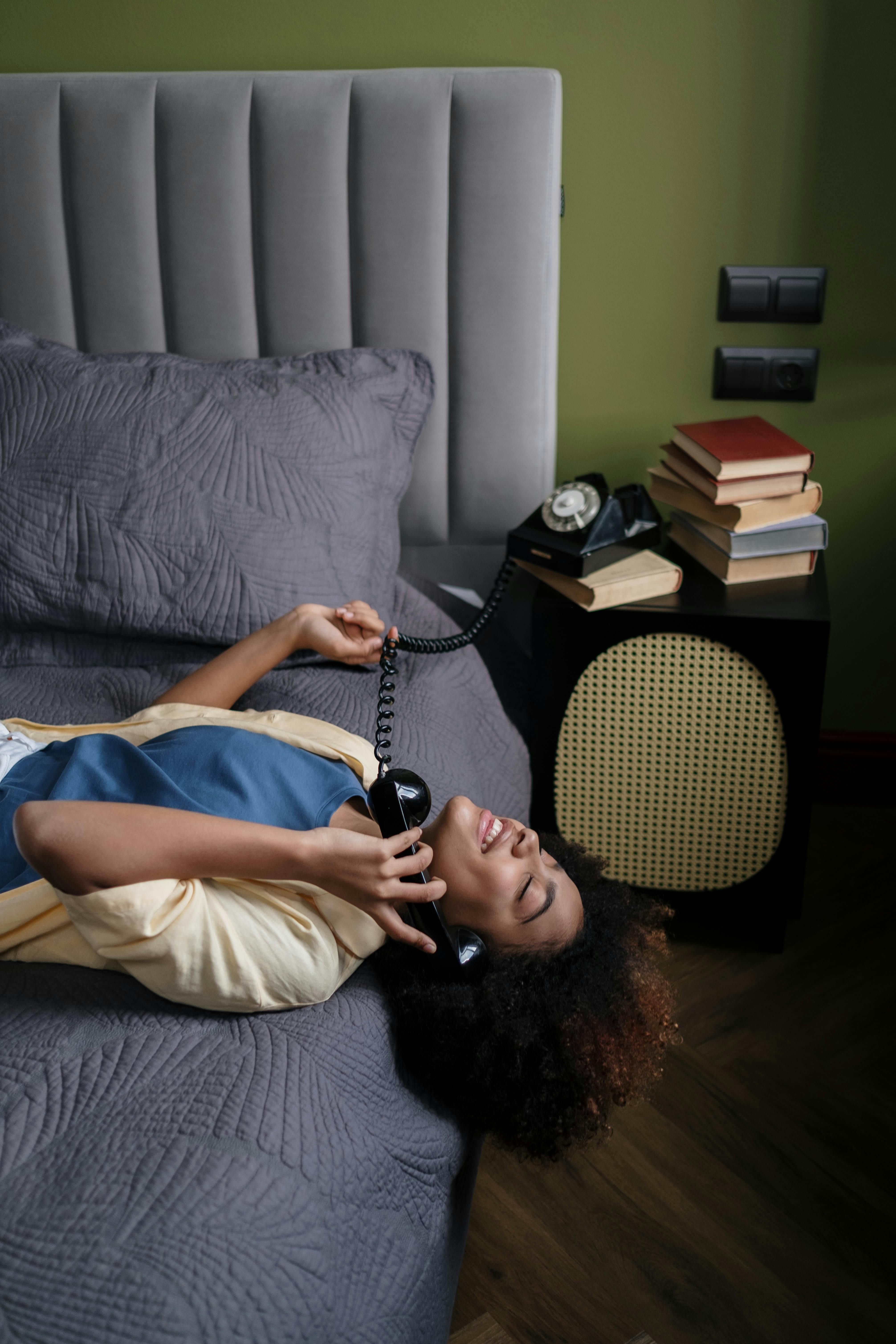 An Afro-Haired Woman Having a Telephone Call while Lying on the Bed ...