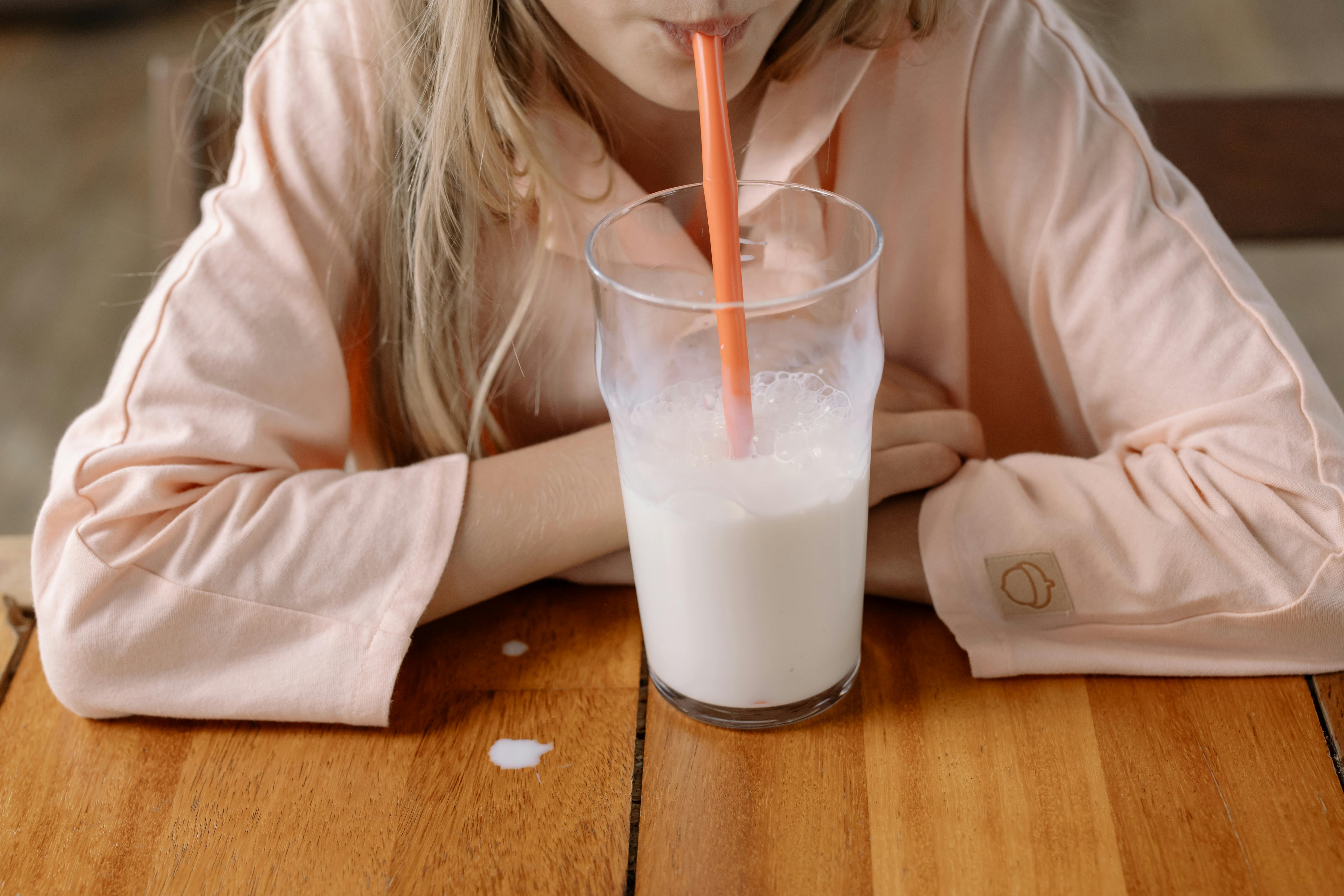 Photo of a Girl in a Pink Shirt Sipping Milk from a Red Straw · Free ...