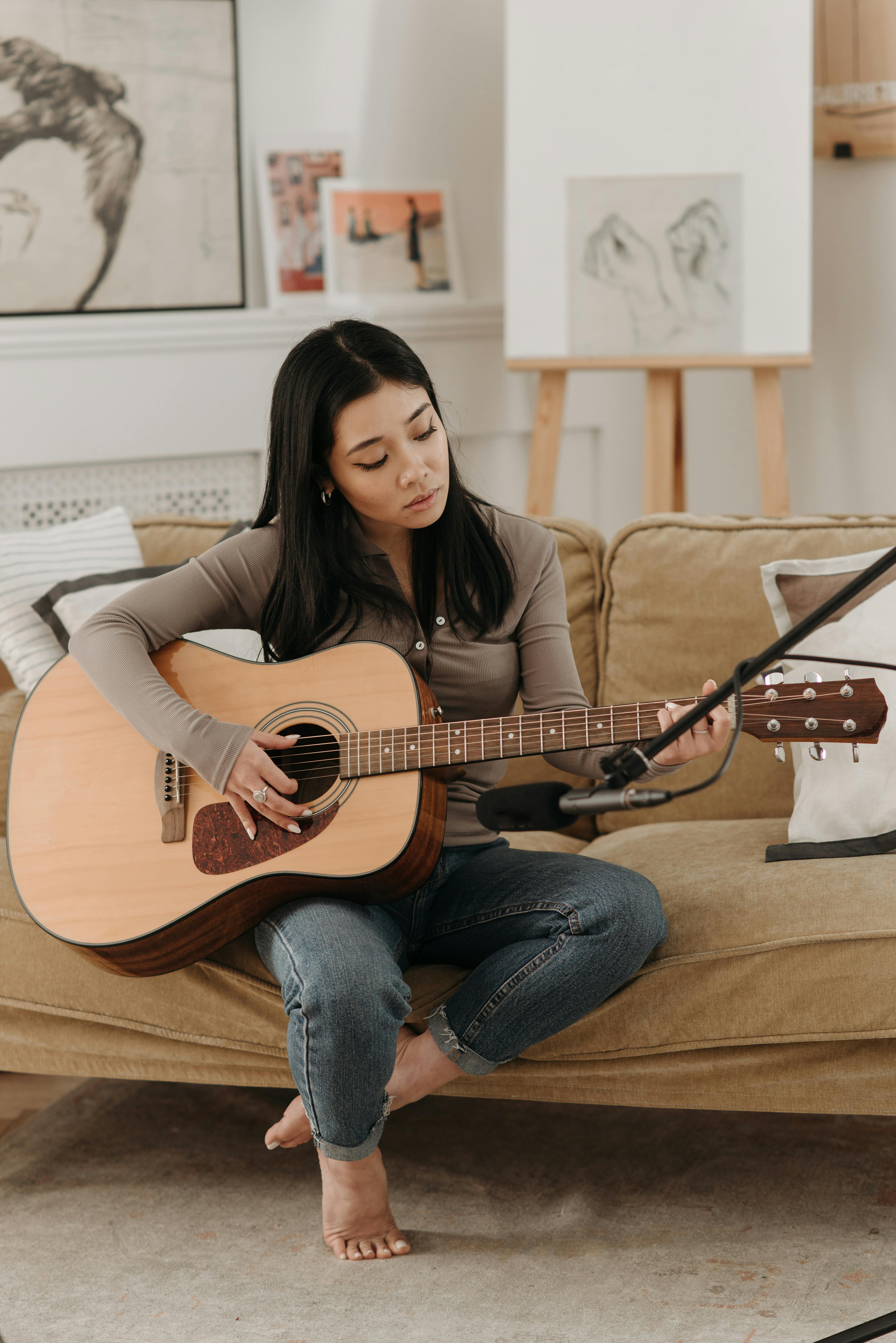 Photo of a Woman Playing an Acoustic Guitar while Sitting on a Brown ...