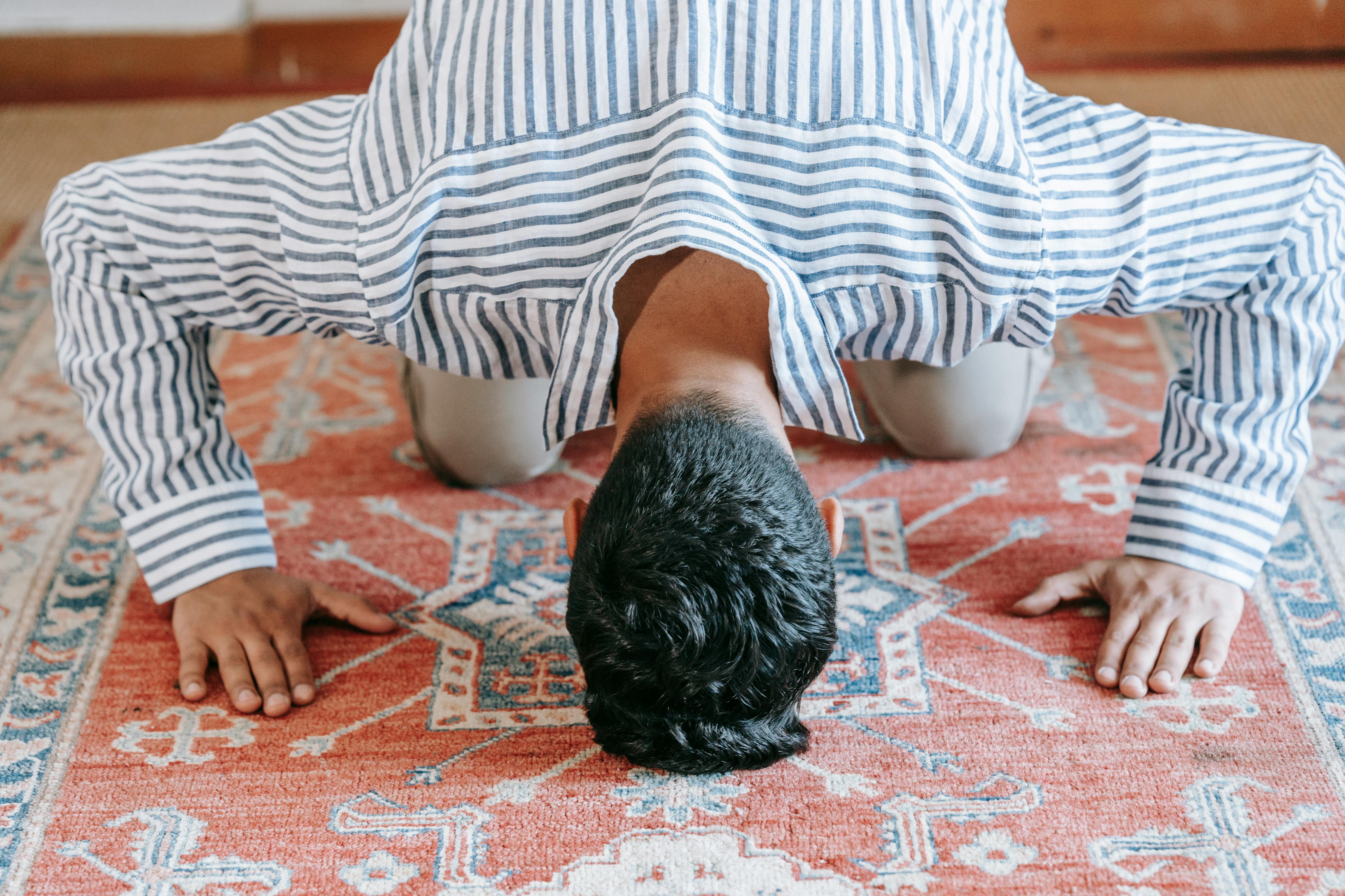Man in White Thobe Bowing Down on Red and Blue Rug · Free Stock Photo