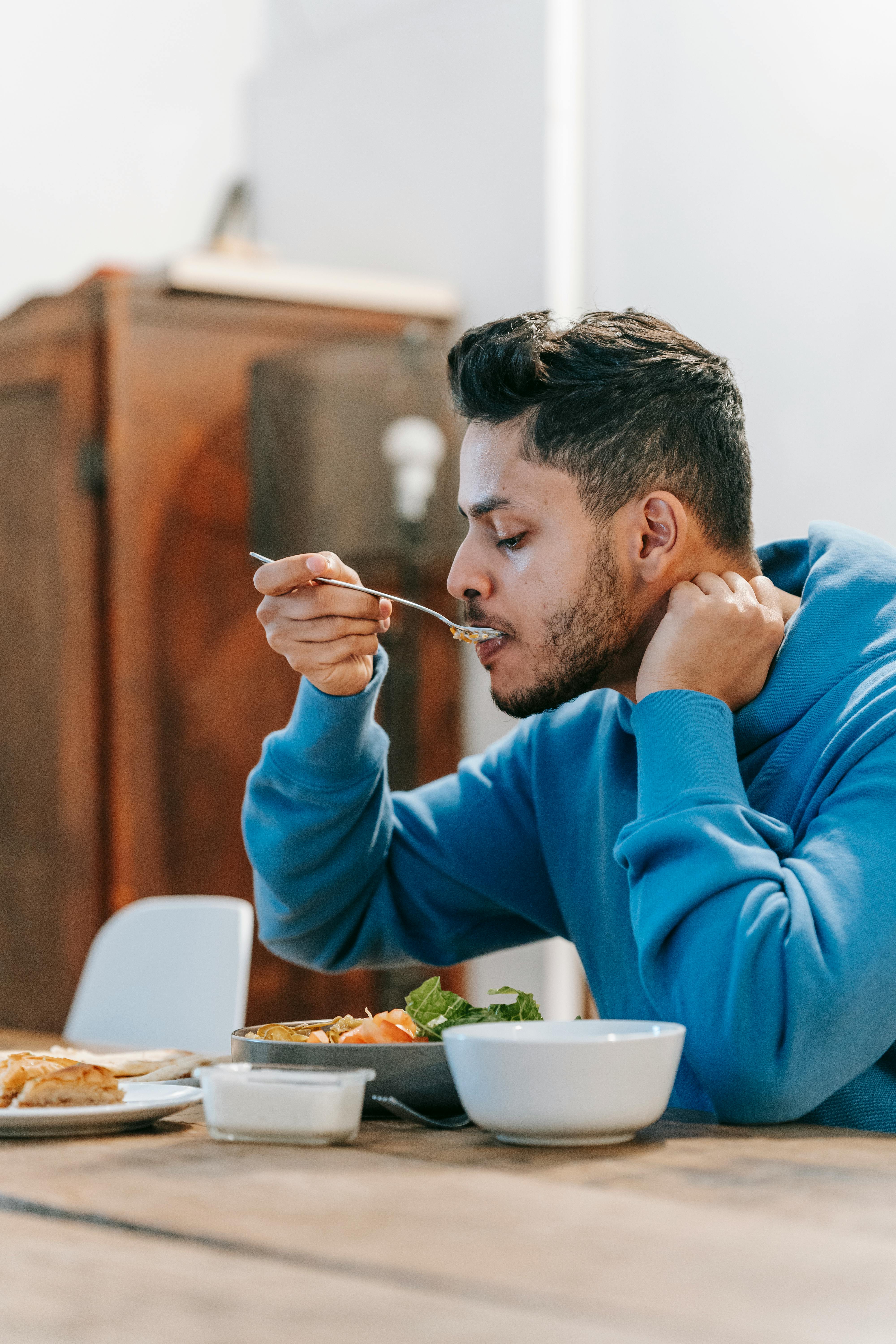 Indian man sitting at table and eating food · Free Stock Photo
