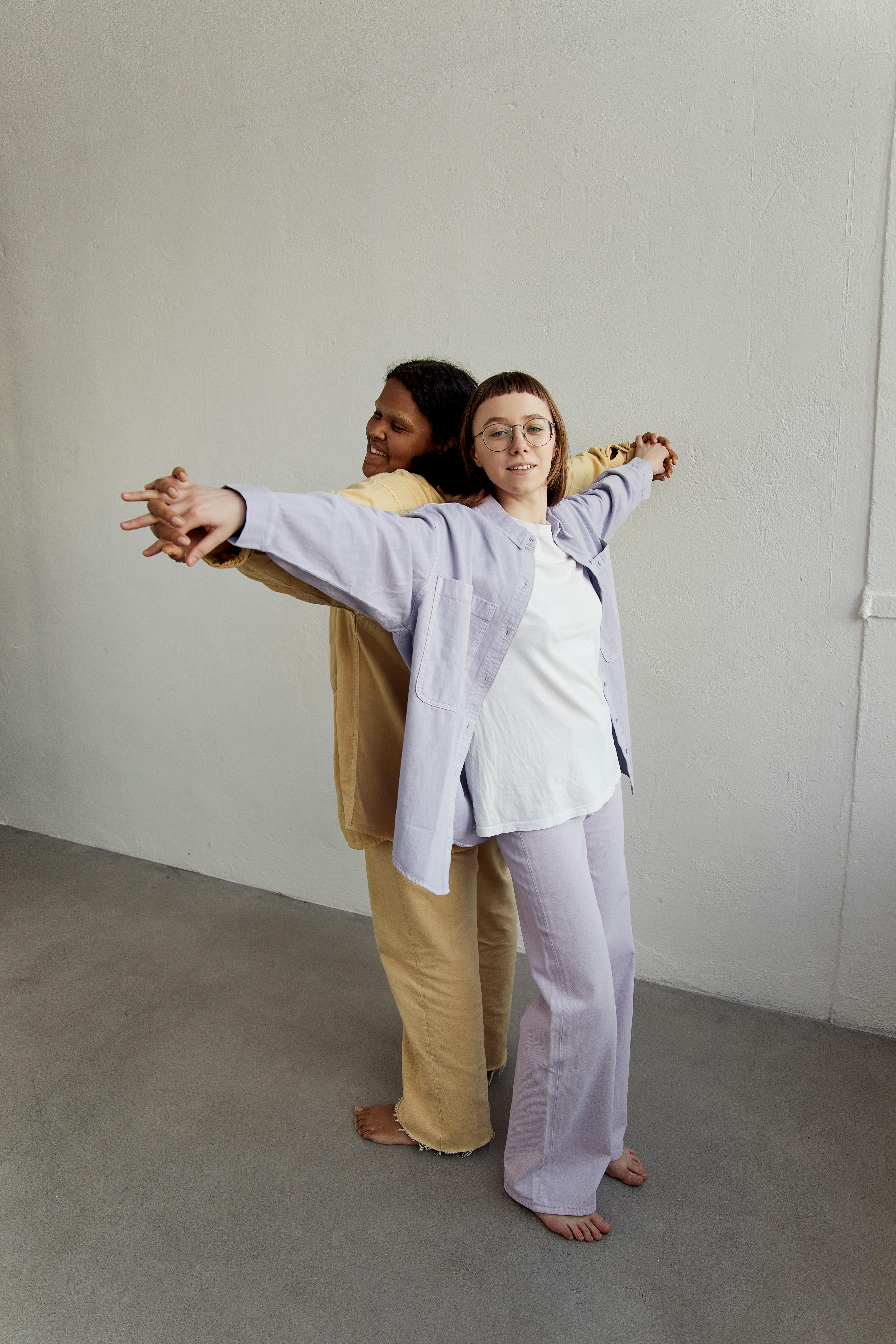 Women Standing Near White Wall Standing Back to Back · Free Stock Photo