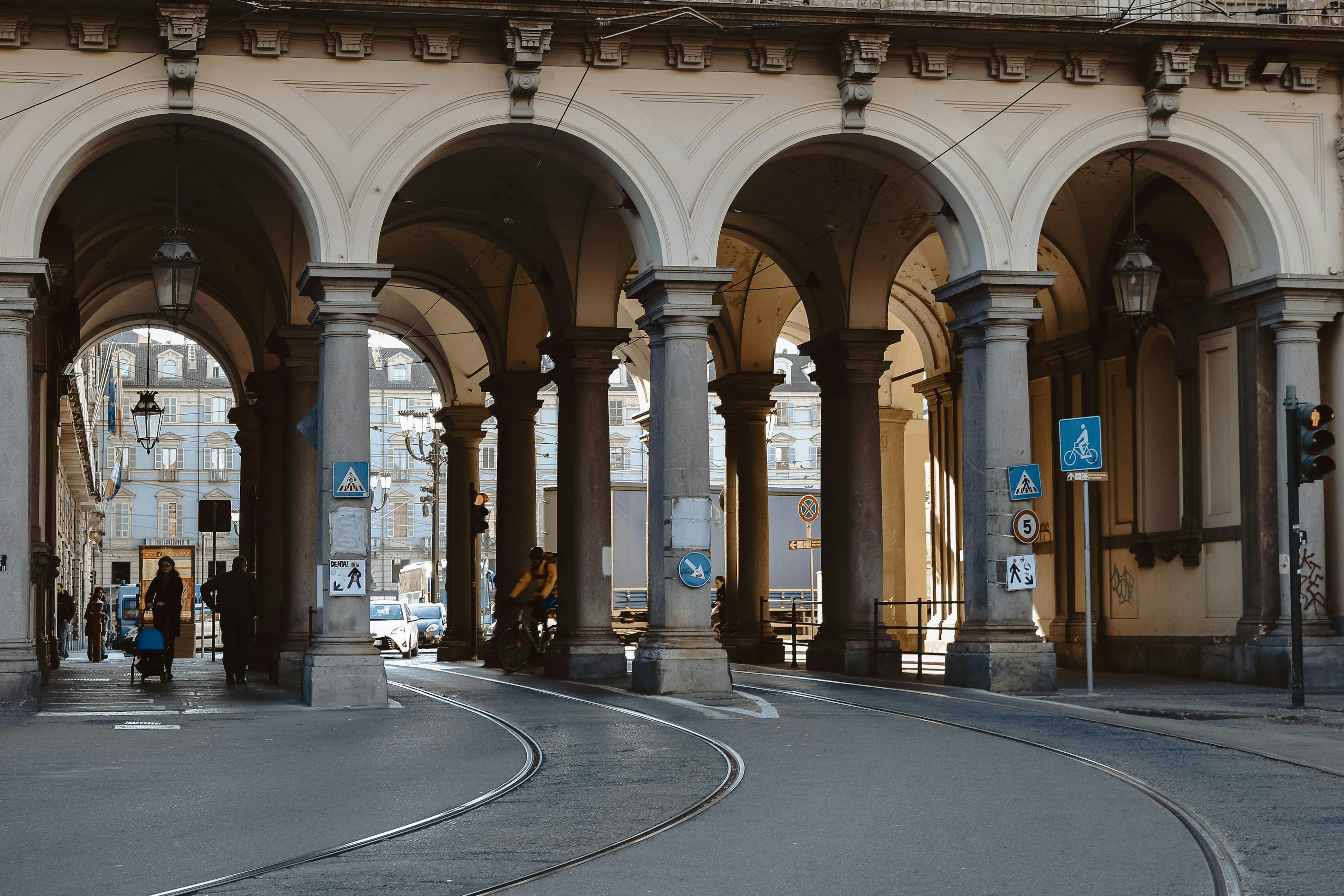 Tramways on urban road under old arched building · Free Stock Photo