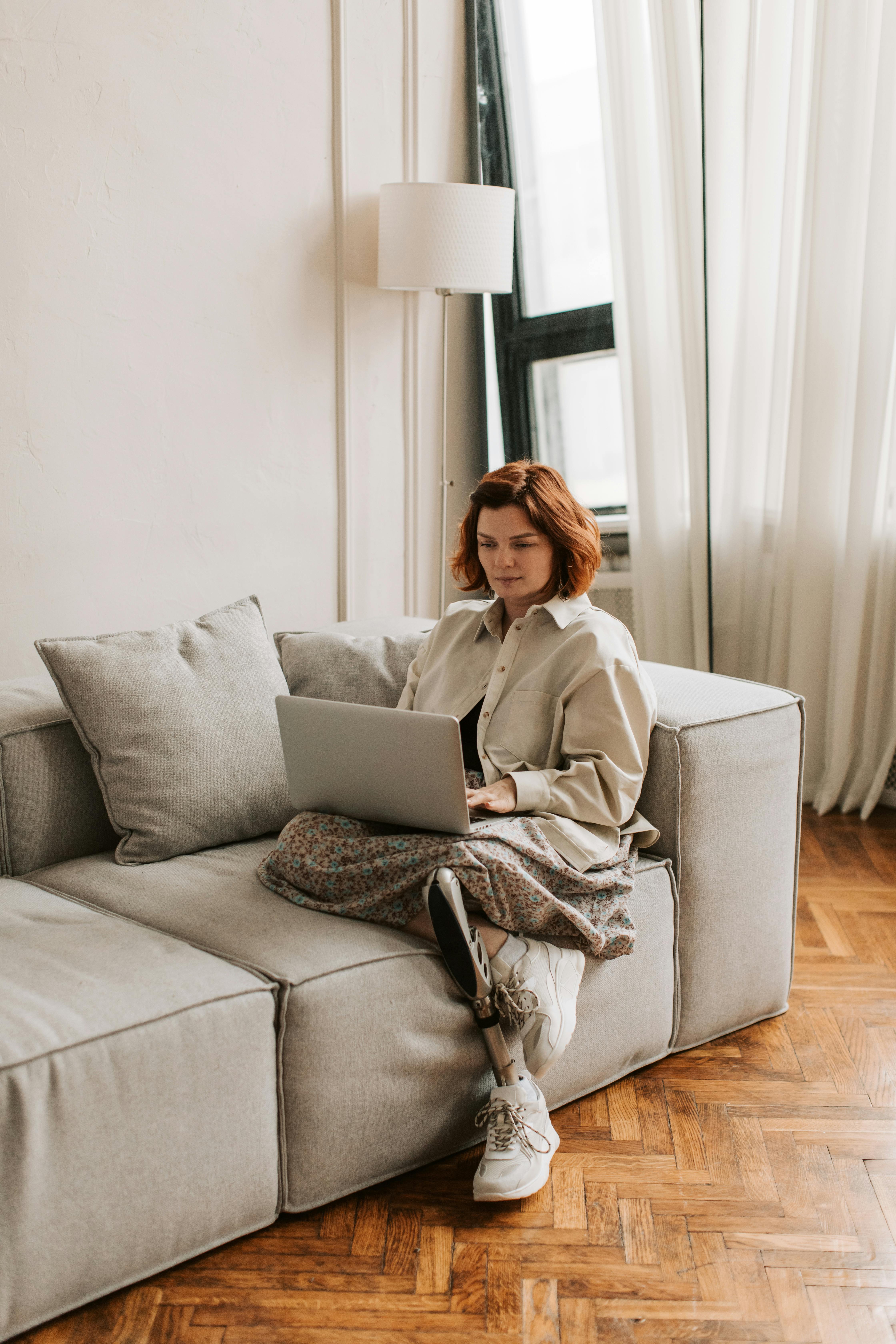 Woman sitting on a Sofa using Laptop · Free Stock Photo