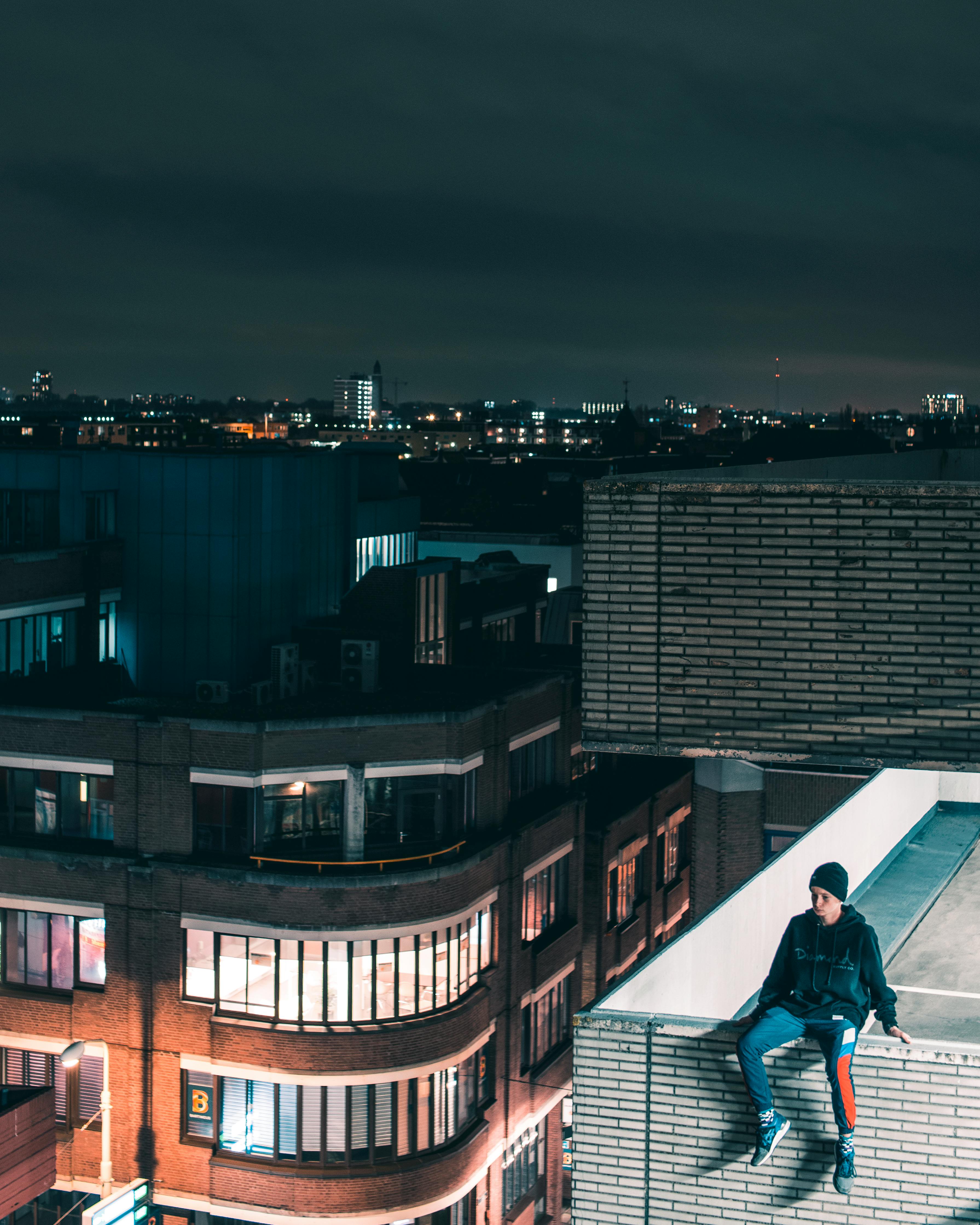 Man Wearing Black Jacket Sitting On Building Rooftop At Nighttime ...