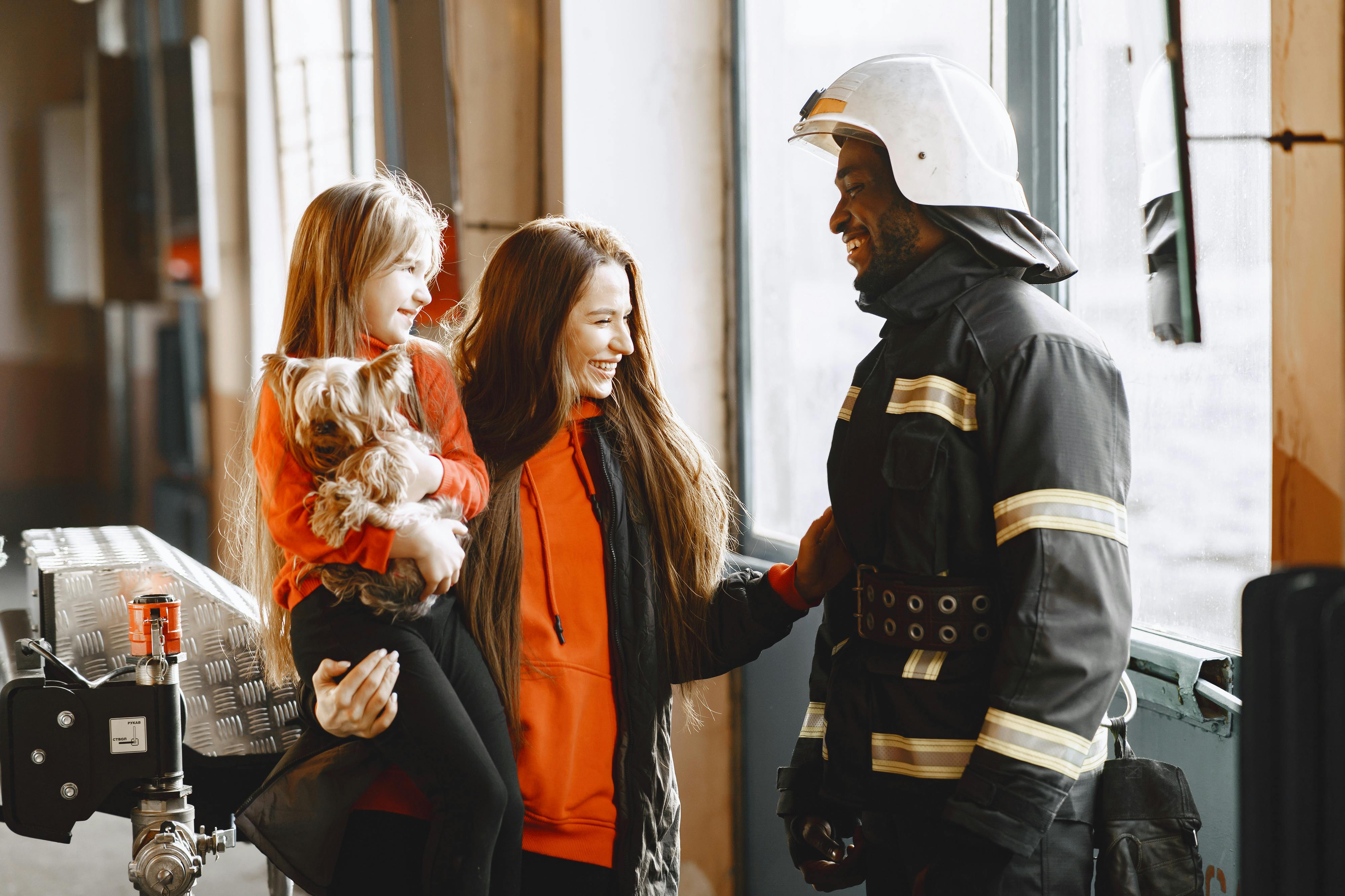 Happy Mother carrying Child in front of a Fireman · Free Stock Photo