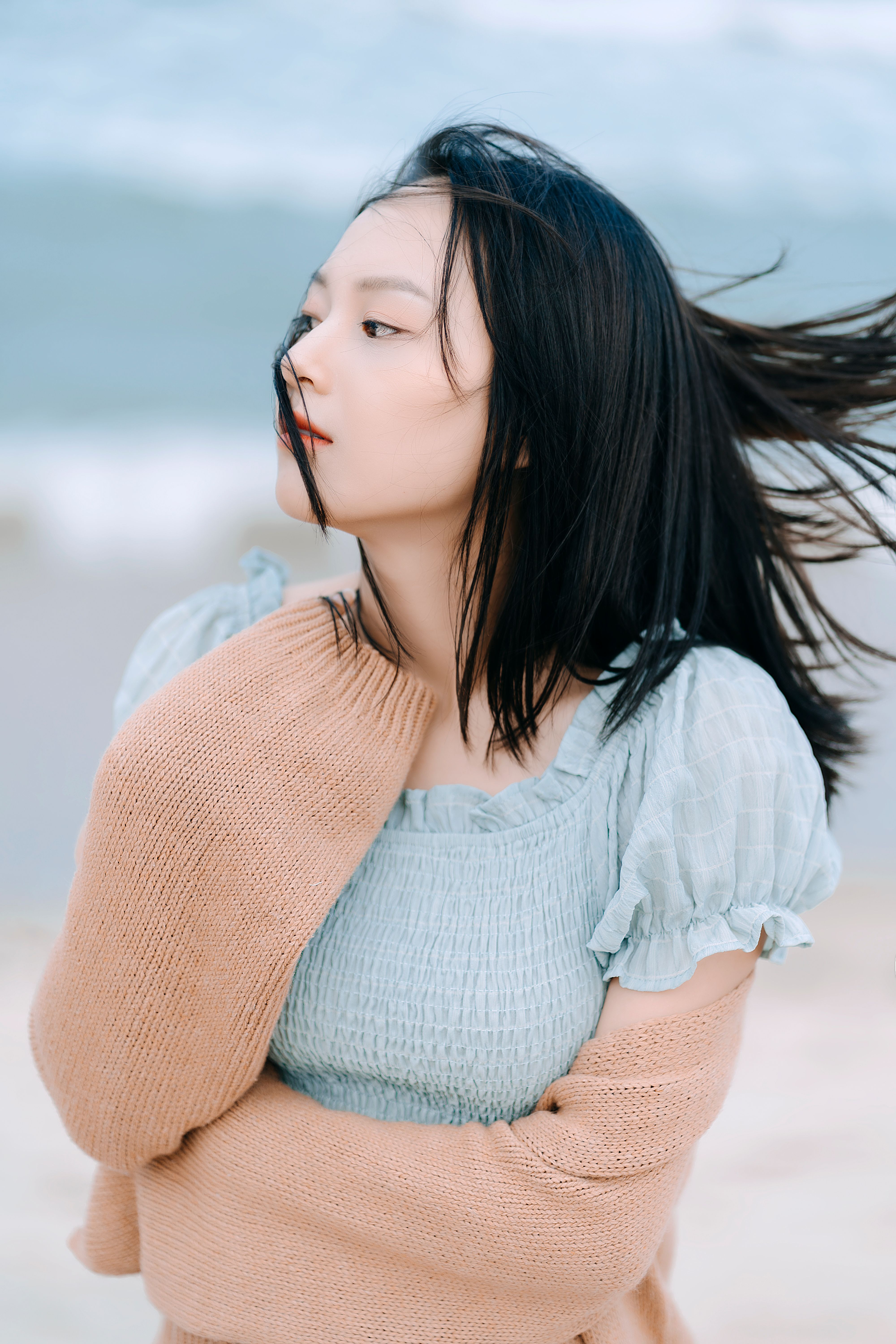 Dreamy Asian woman with flying hair standing on seashore · Free Stock Photo