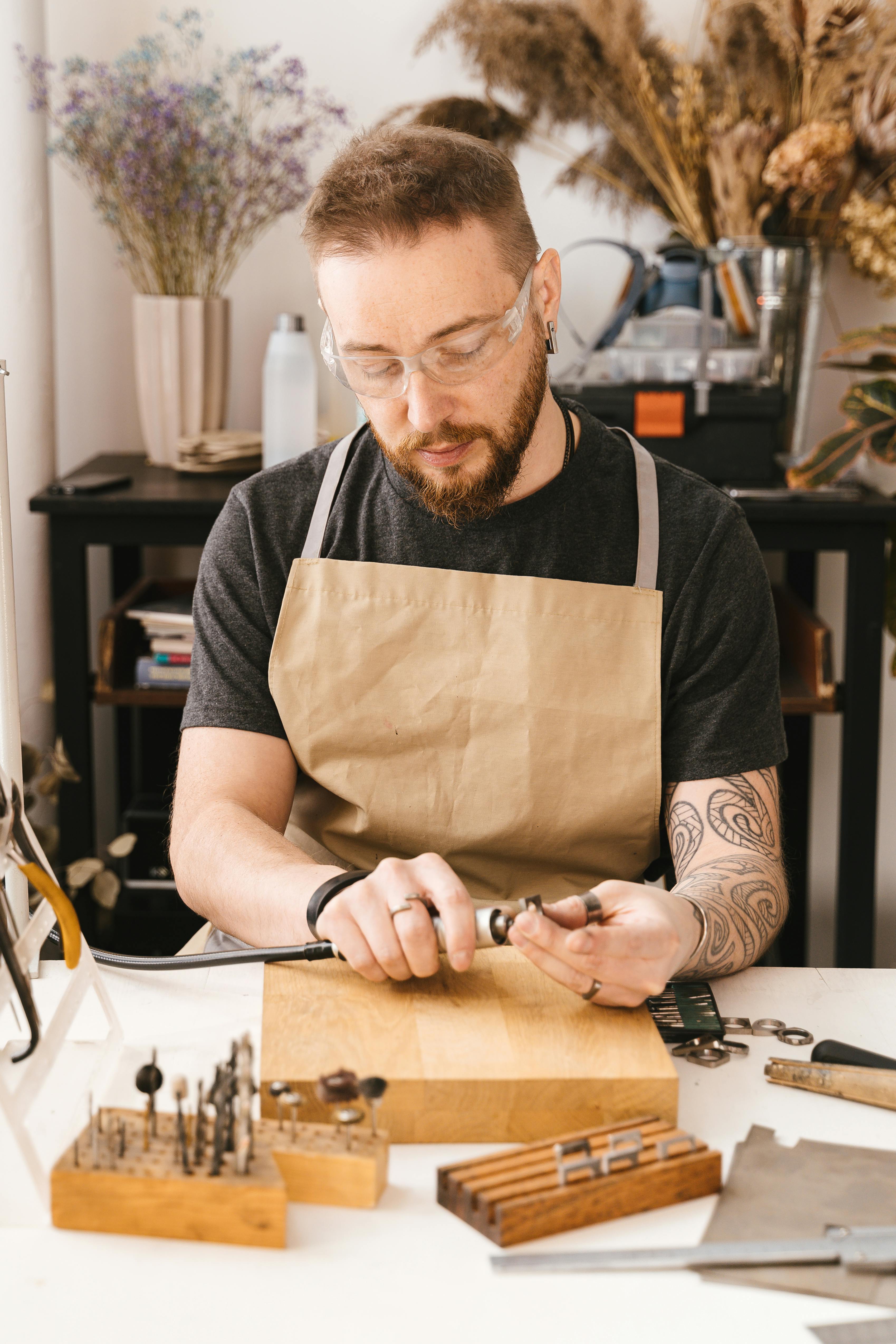 A Man Wearing Protective Goggles and Brown Apron Holding a Grinder ...