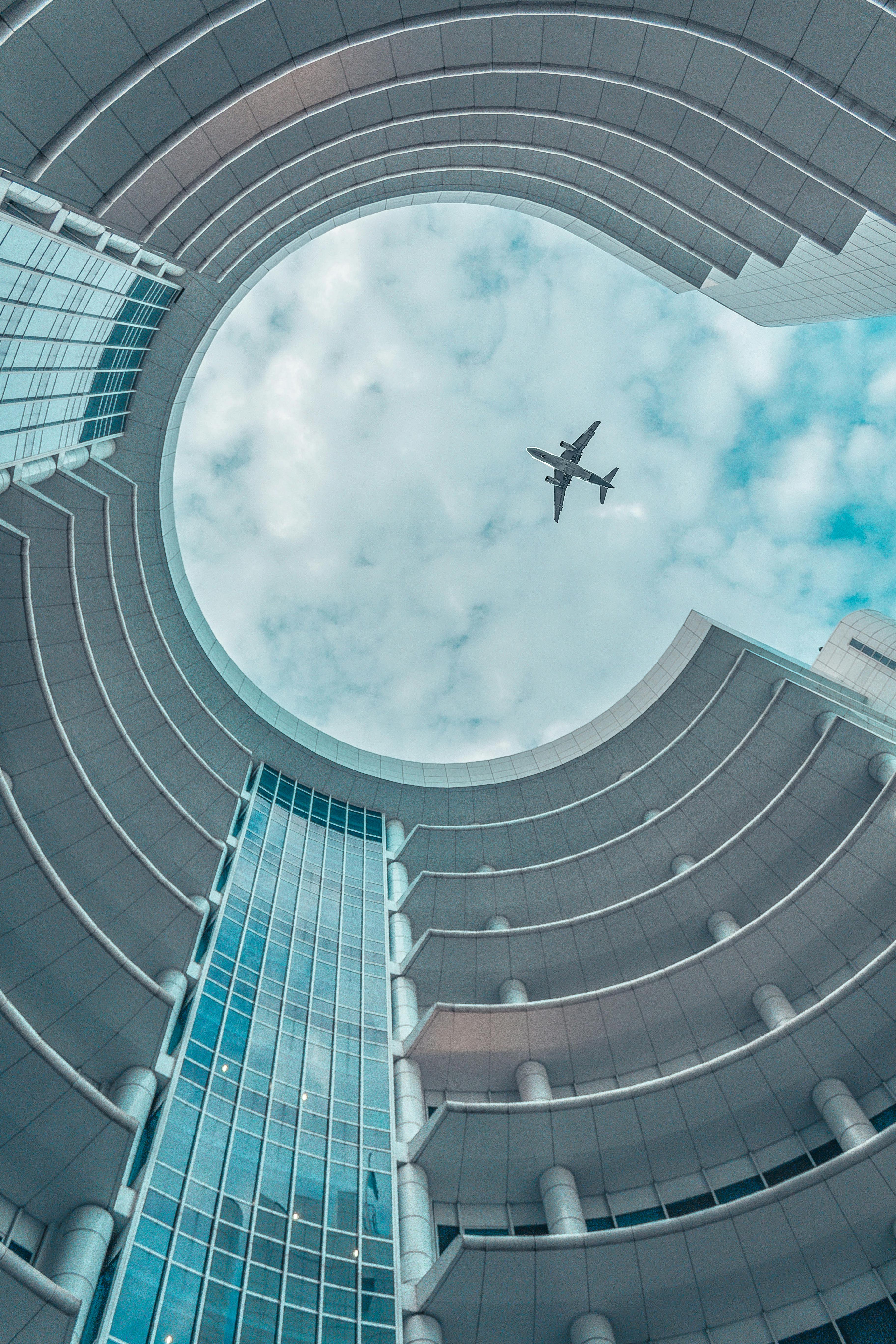 Airplane Flying Over the Circular Building · Free Stock Photo