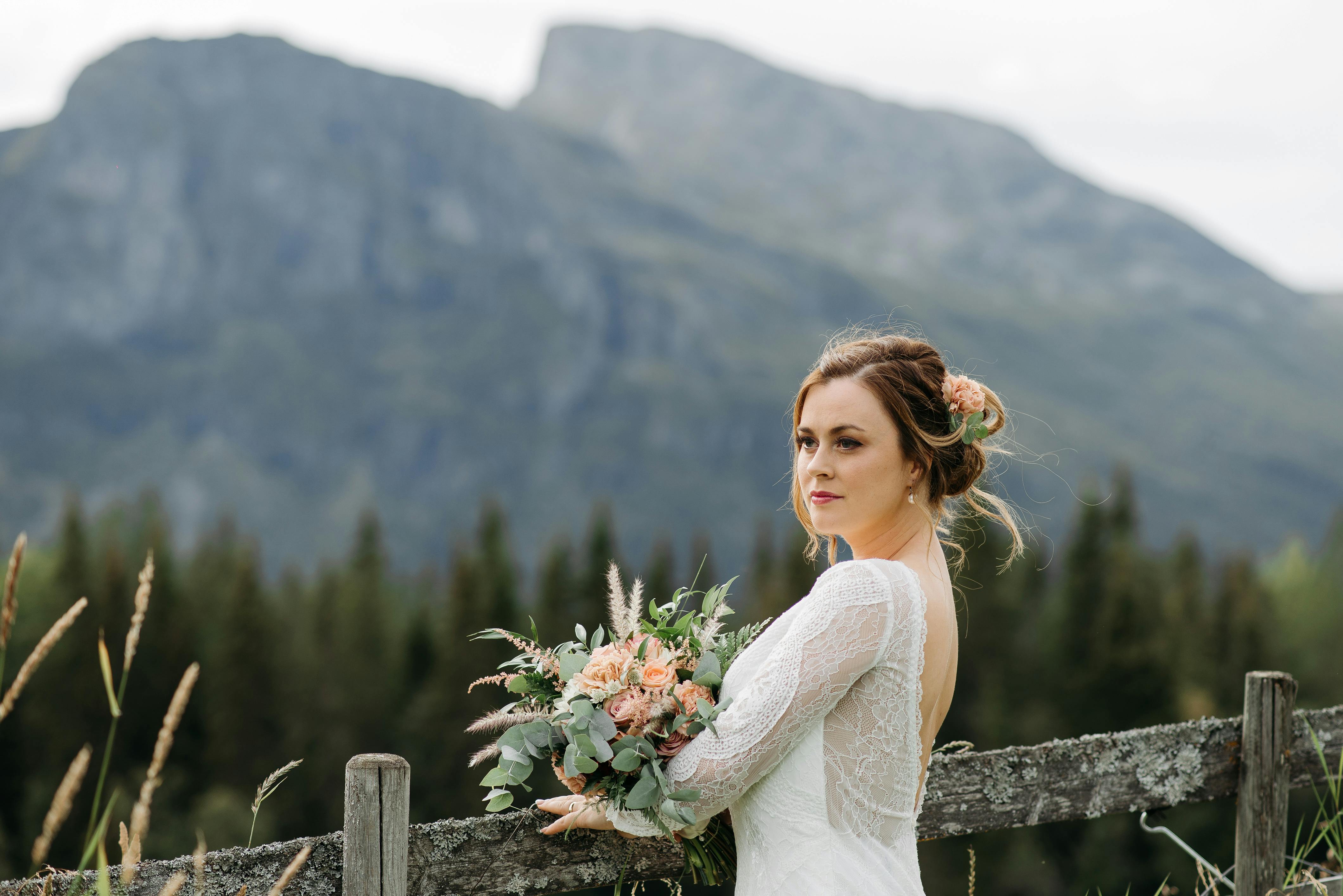 A Beautiful Bride Holding Wedding Bouquet Standing Near Wooden Fence ...