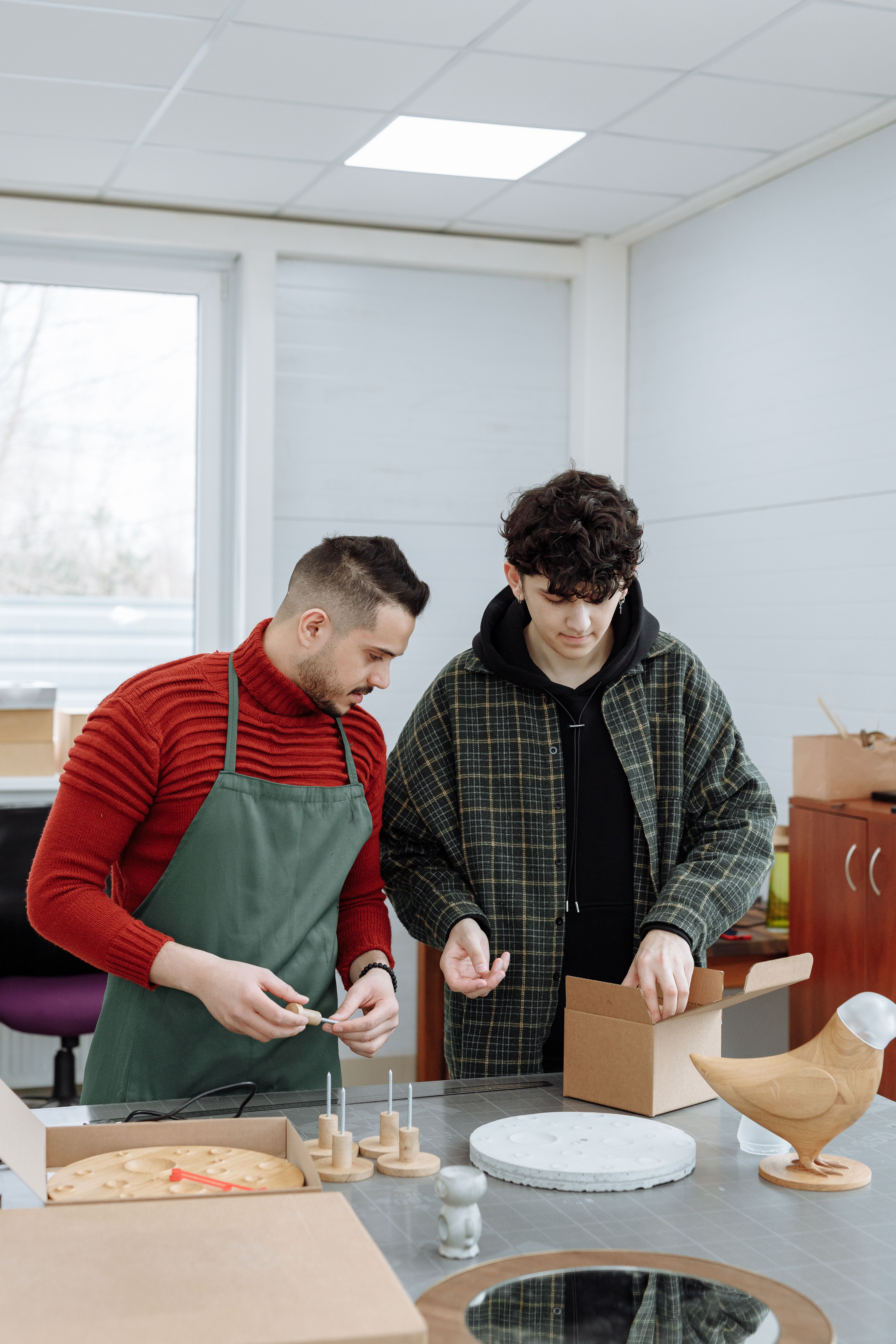 A Man Standing Beside a Table Holding a Cardboard Box Beside a Man ...
