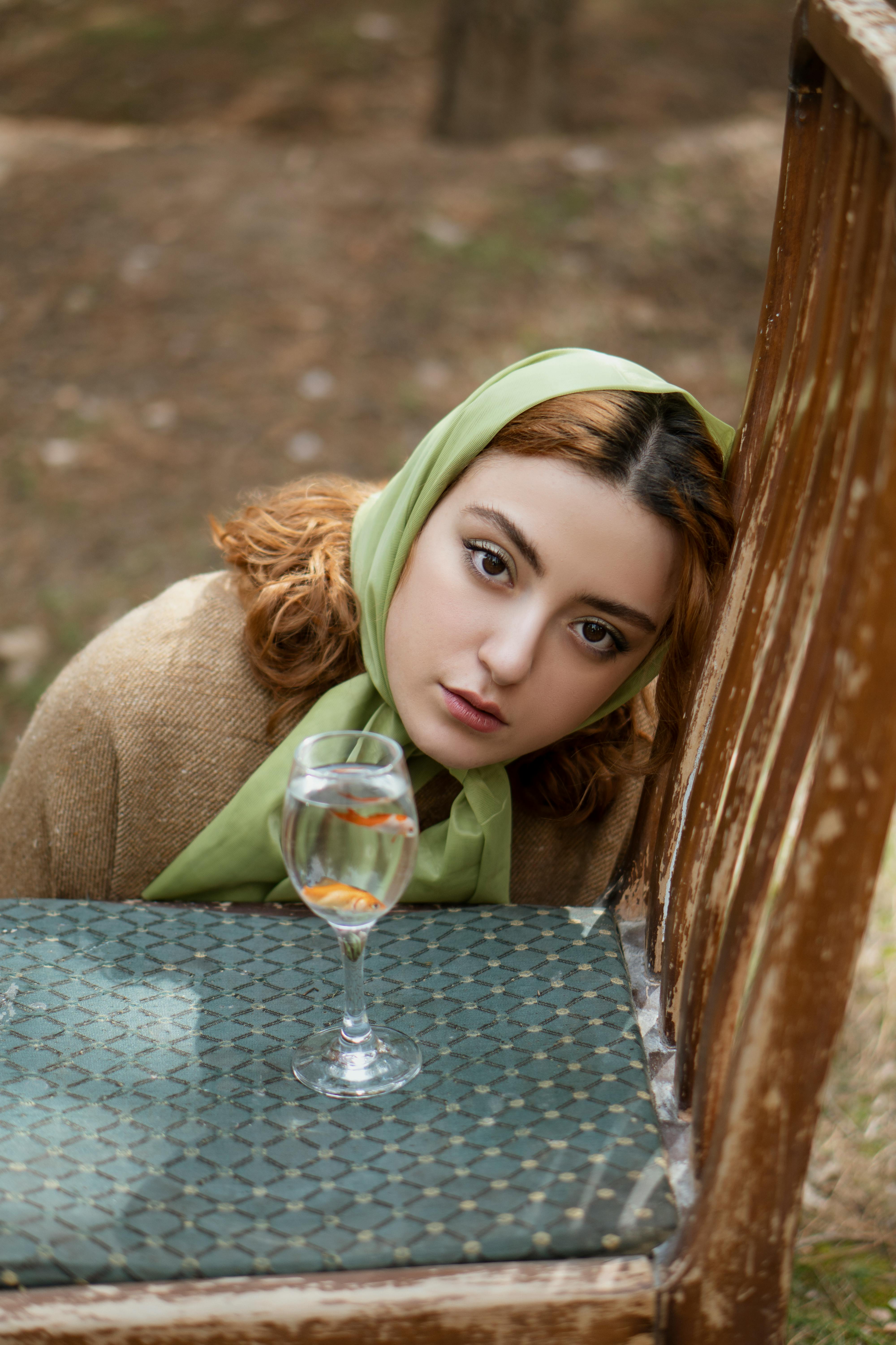 Woman Crouching by a Chair with a Glass on It · Free Stock Photo