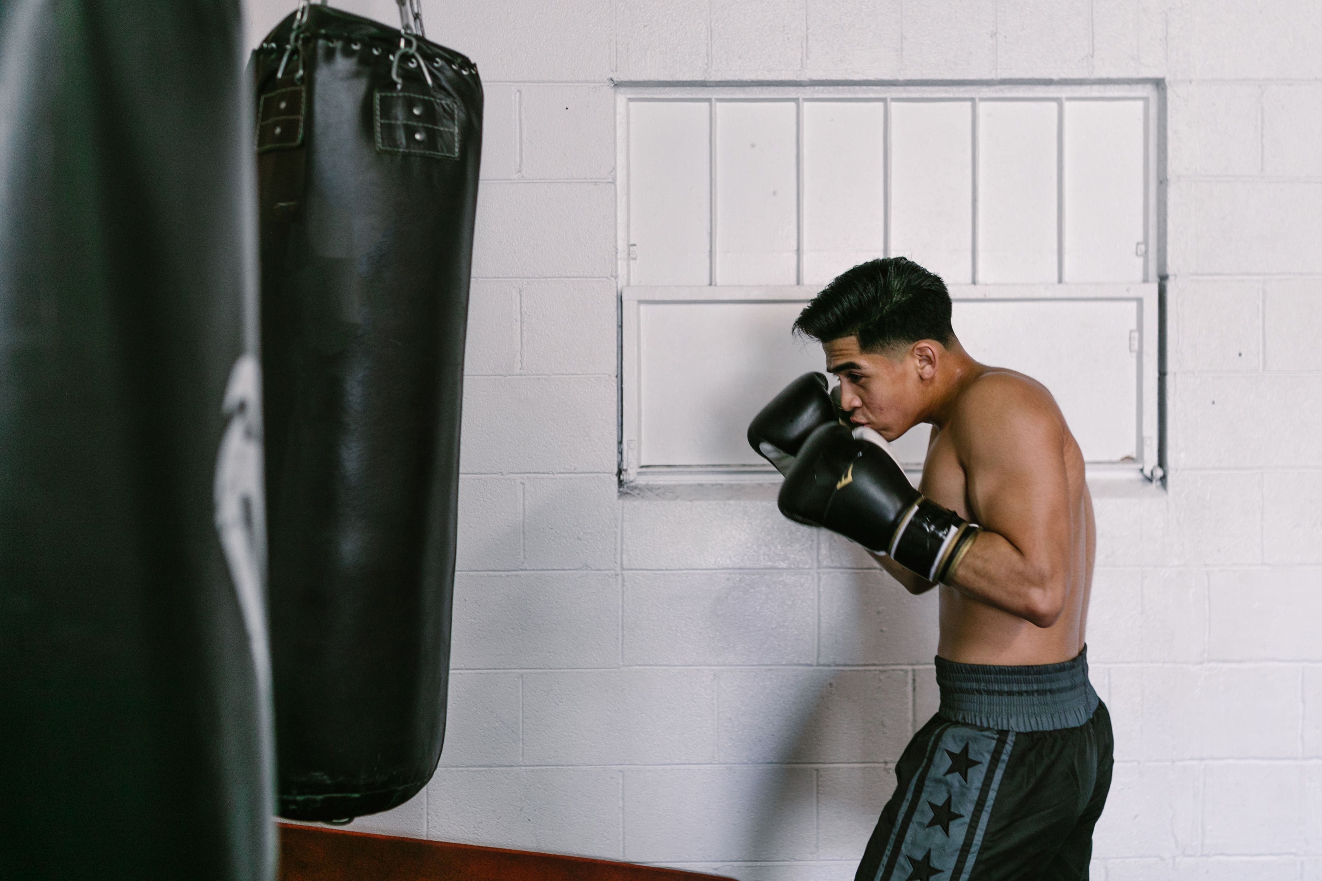 A Grayscale of Man Punching a Punching Bag · Free Stock Photo