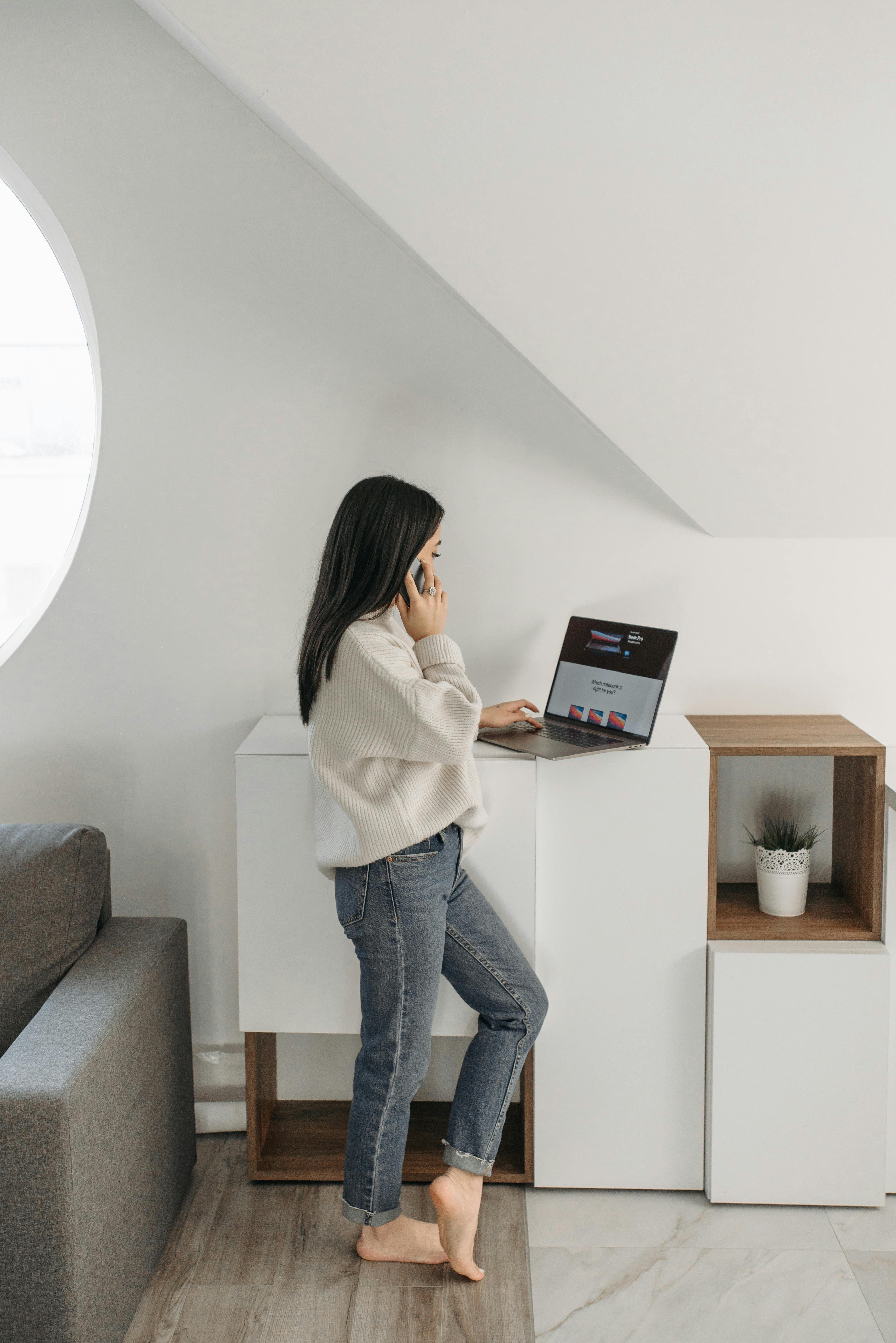 A Woman Talking on the Phone while Using Her Laptop · Free Stock Photo