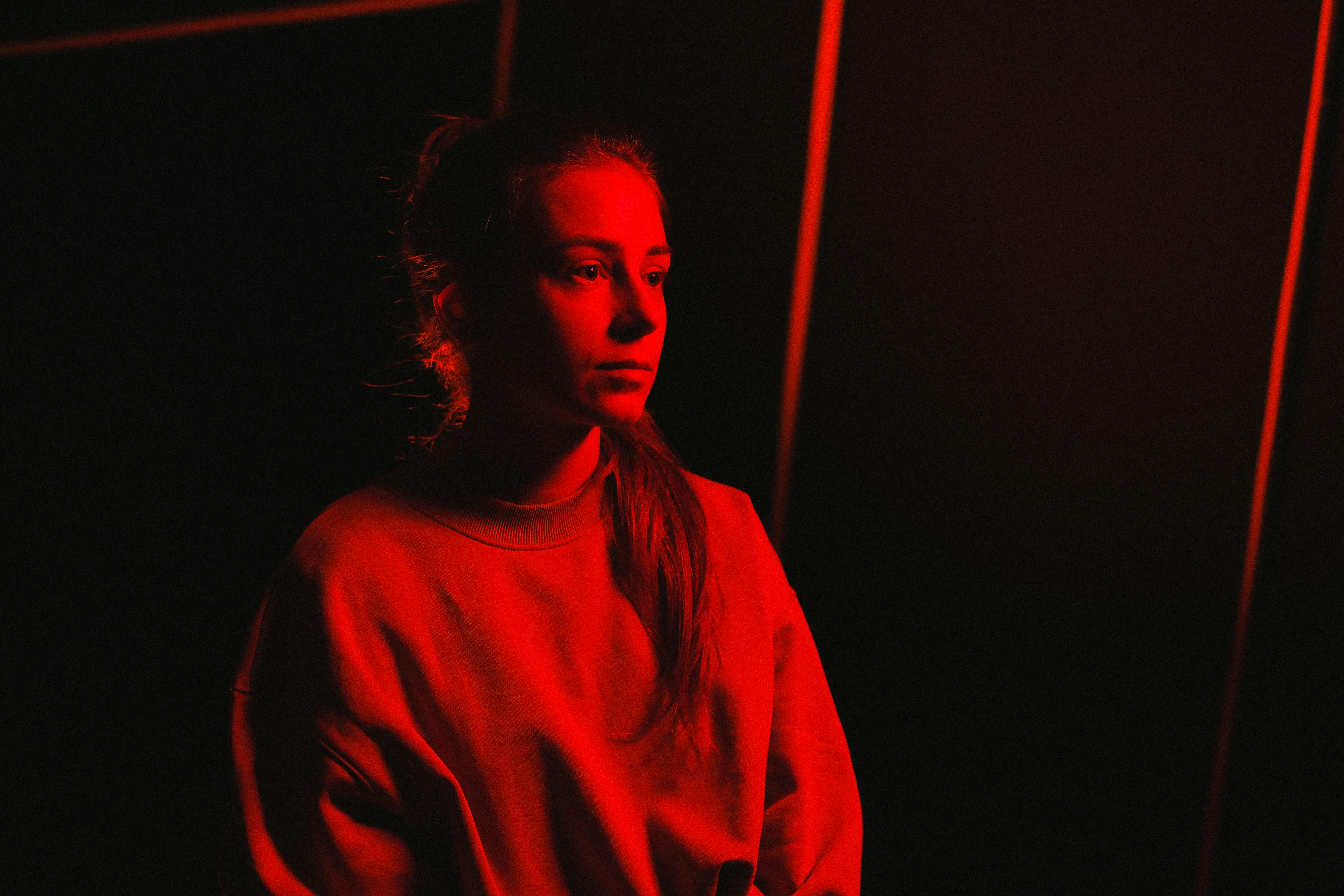 Woman Illuminated in Red Light inside Dark Room · Free Stock Photo