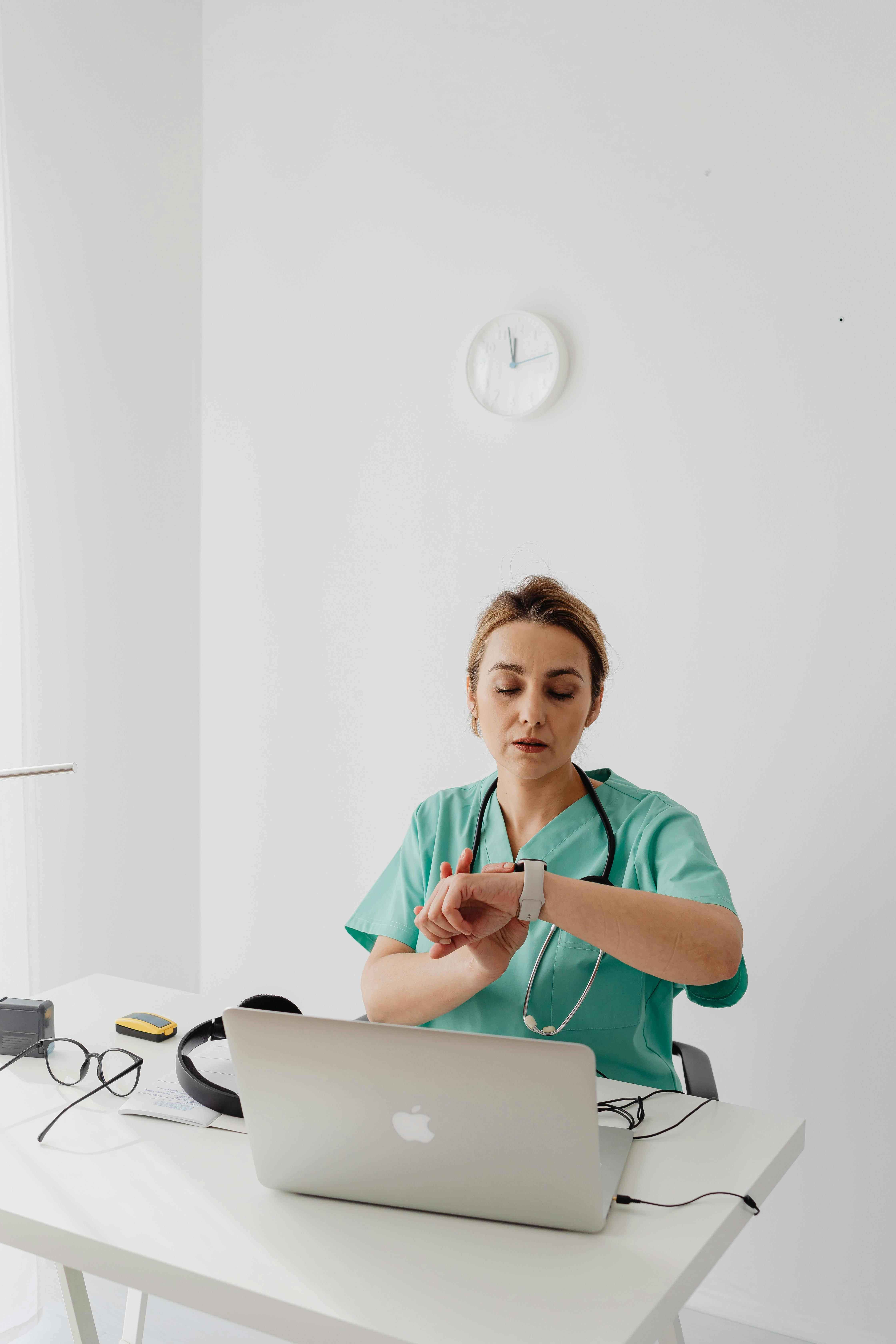 Woman Sitting in Front of Laptop Looking at Her Watch · Free Stock Photo