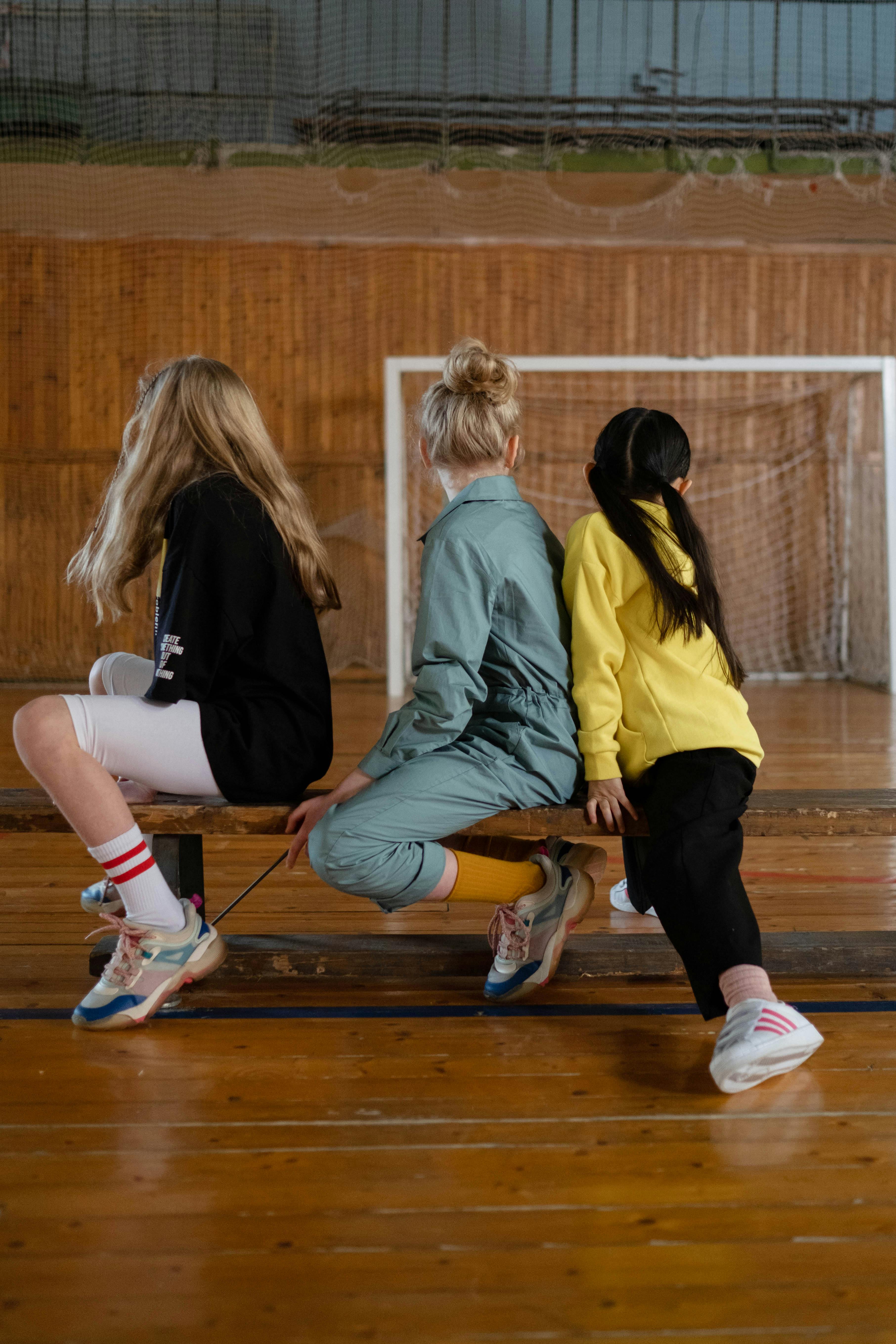 Back View of Girls Sitting on Brown Wooden Bench · Free Stock Photo