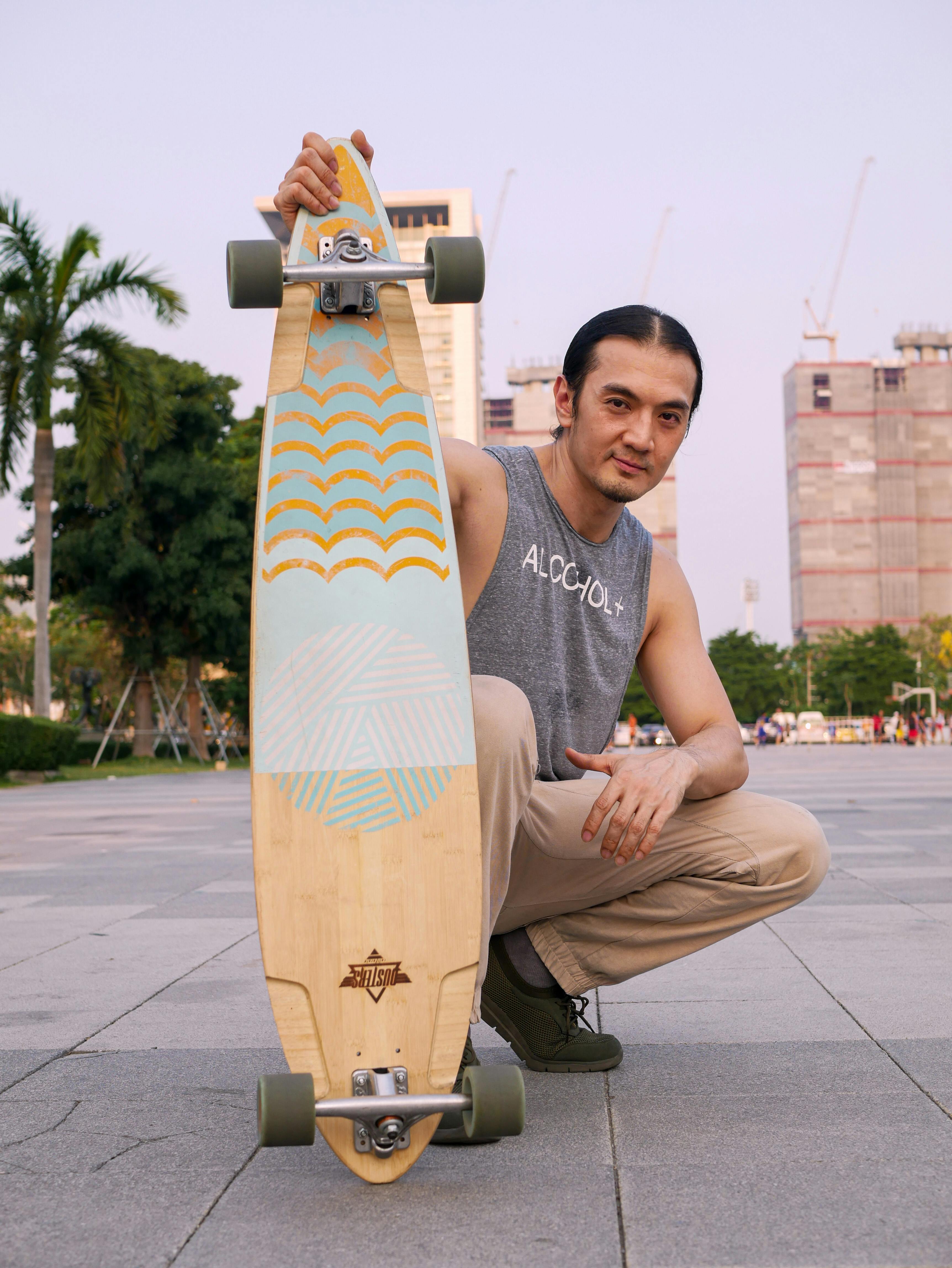 Man In Blue Top Carrying A Longboard · Free Stock Photo