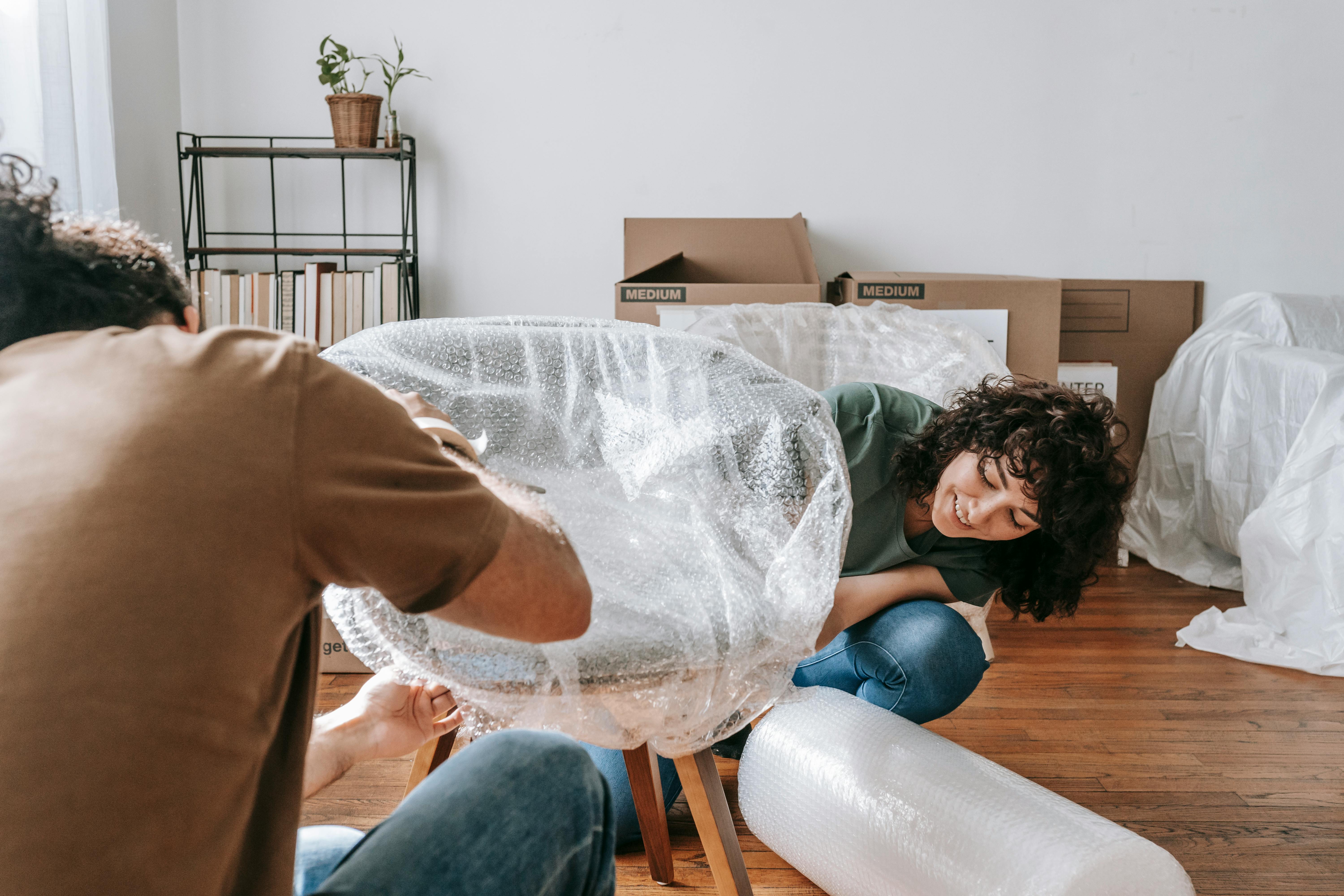 Couple Wrapping A Chair With Plastic · Free Stock Photo