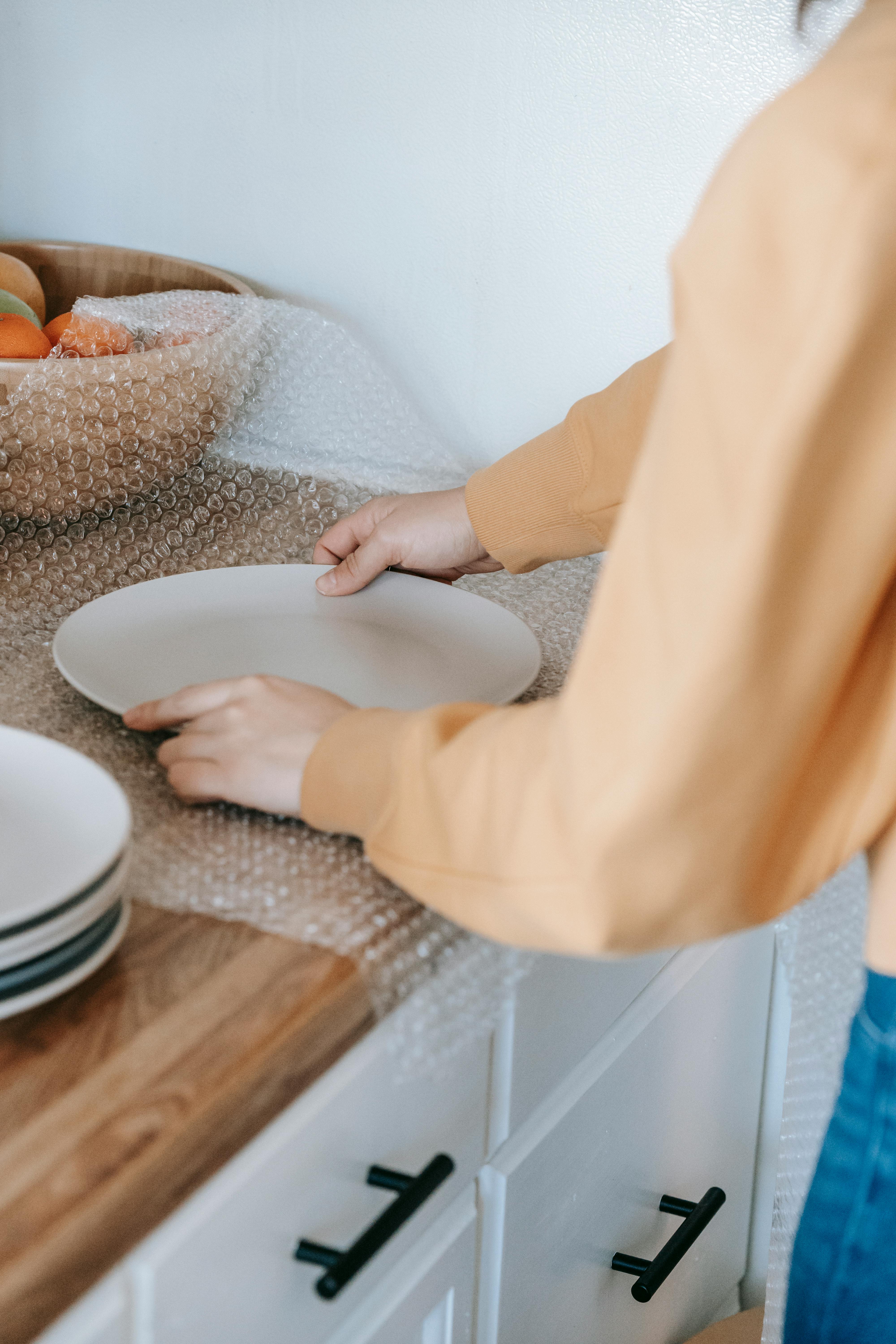 Woman Wrapping Plates With A Bubble Wrap · Free Stock Photo